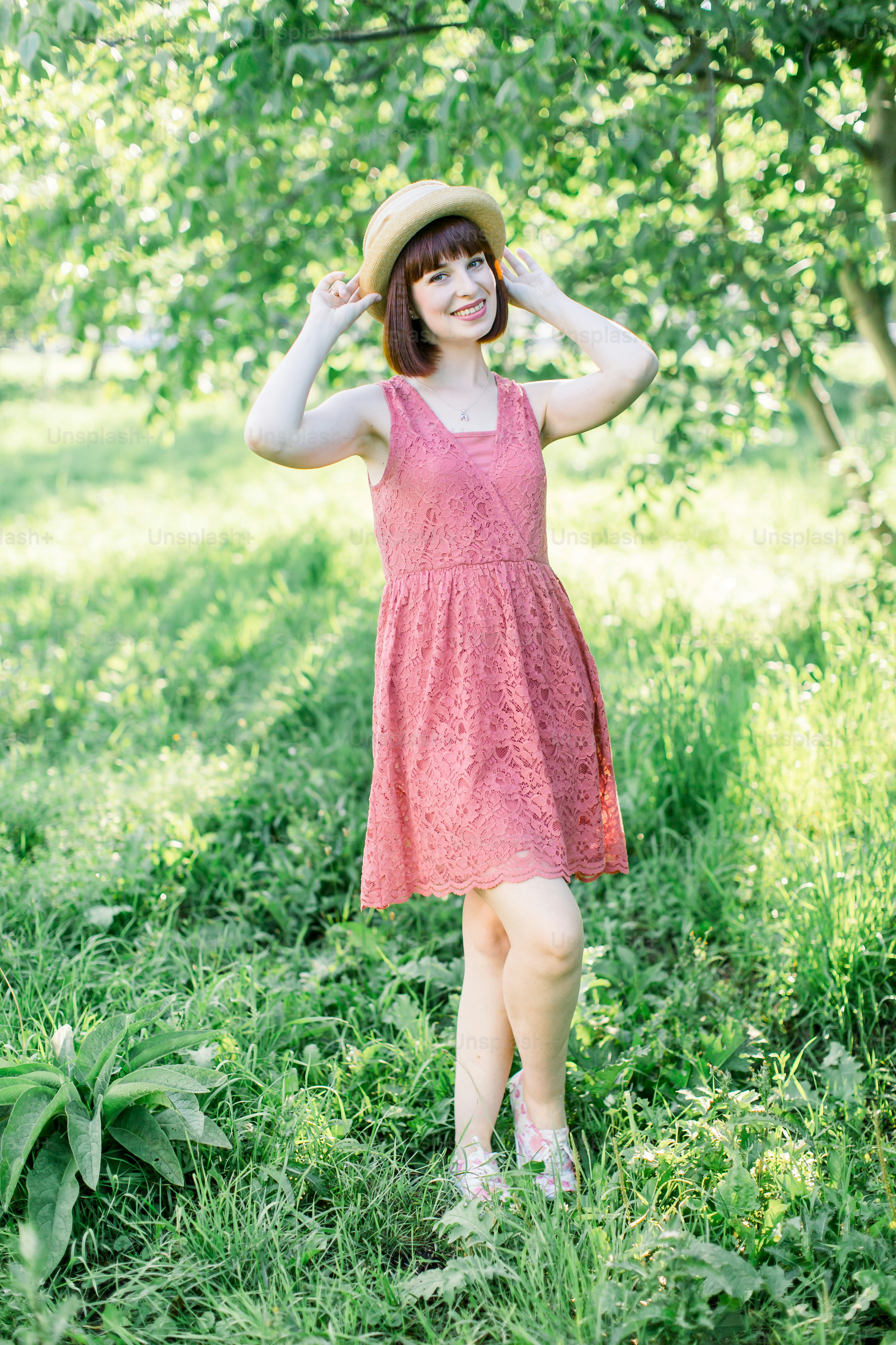 Foto zum Thema Schönes rothaariges Mädchen steht auf dem Apfelgartenhintergrund Sie hält ihren ...