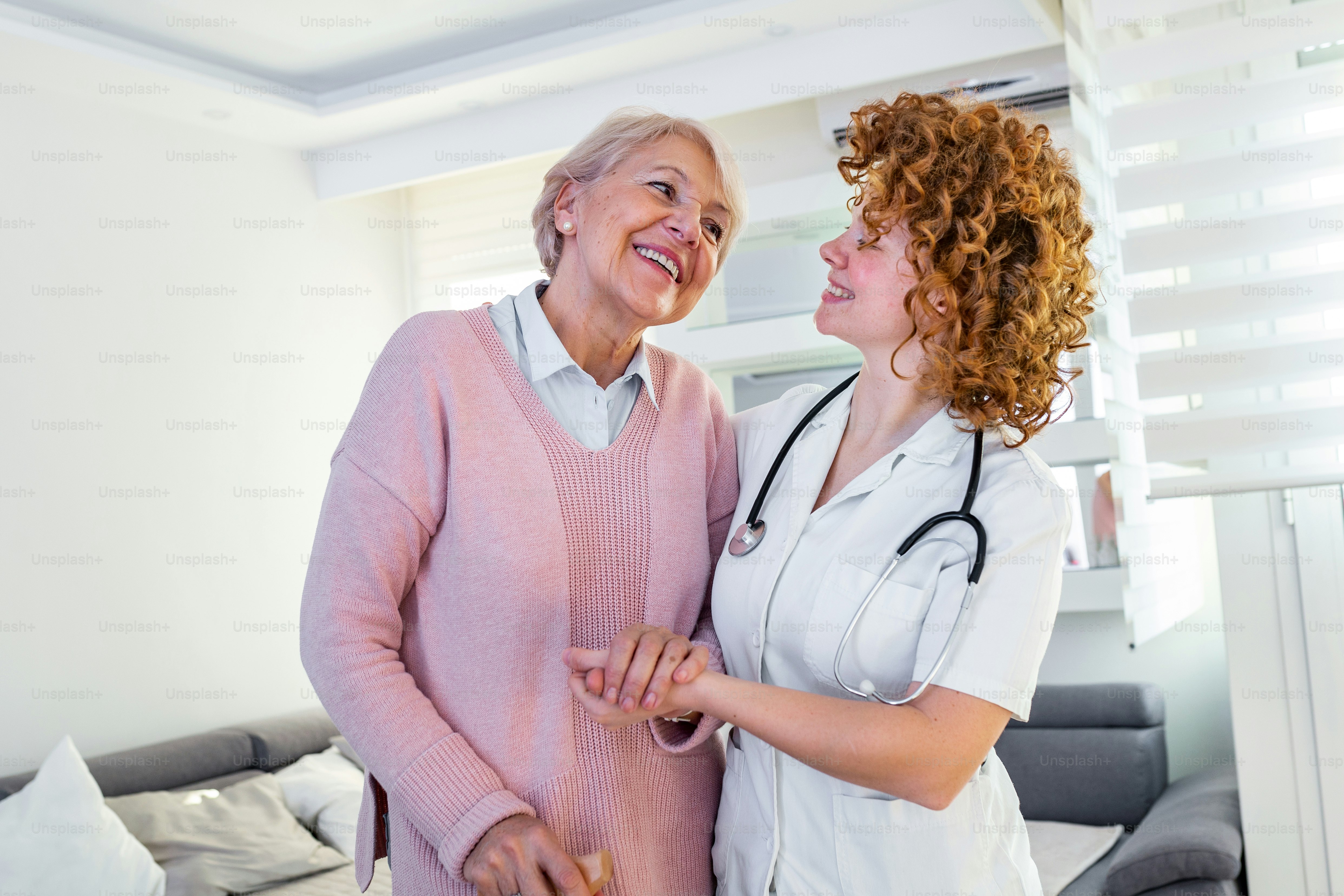 Smiling nurse helping senior lady to walk around the nursing home ...