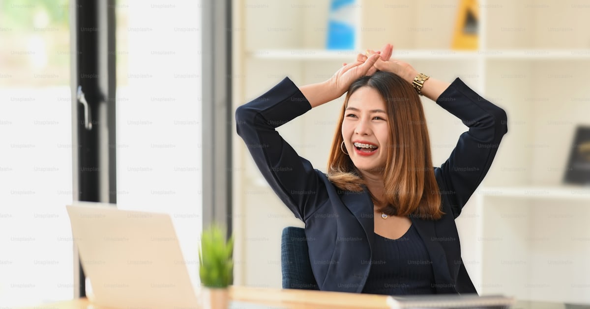 편안한 사무실을 배경으로 나무 작업 테이블에서 작업을 마친 후 휴식을 취하는 검은색 정장을 입은 젊은 아름다운 사업가의 사진