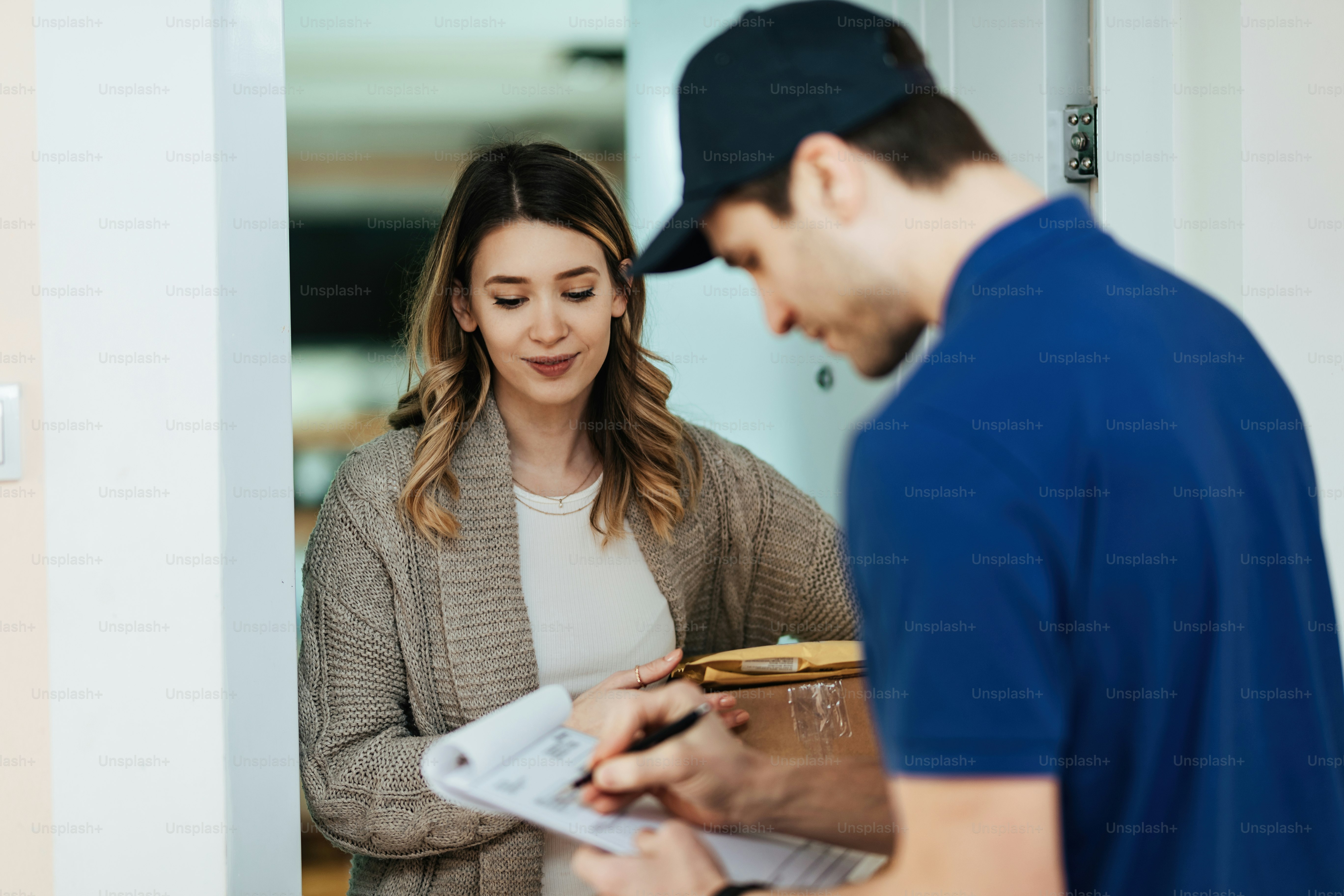 Smiling woman receiving package and waiting for a delivery man to fill ...