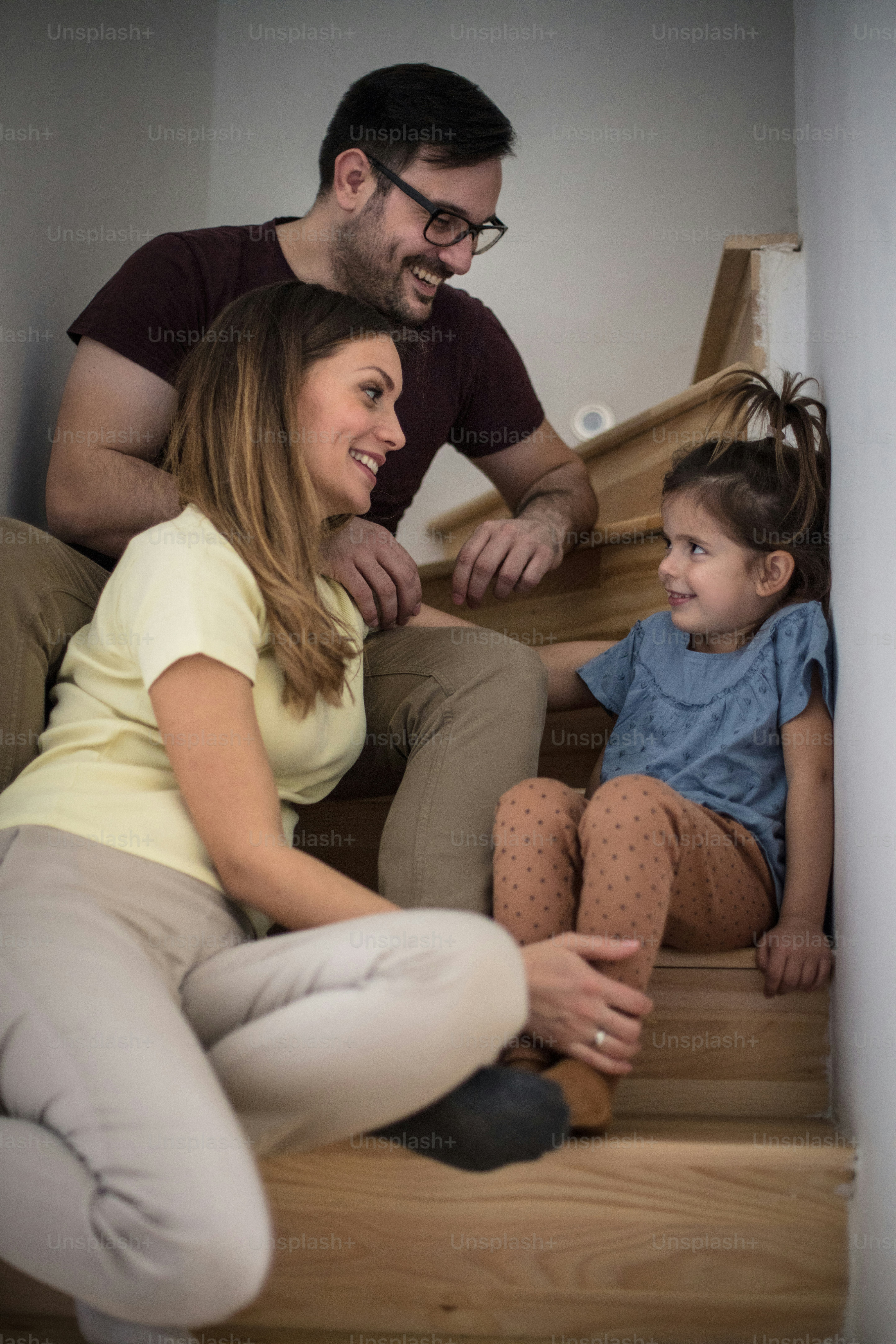Family is pure happiness. Parents with daughter sitting on stairs ...