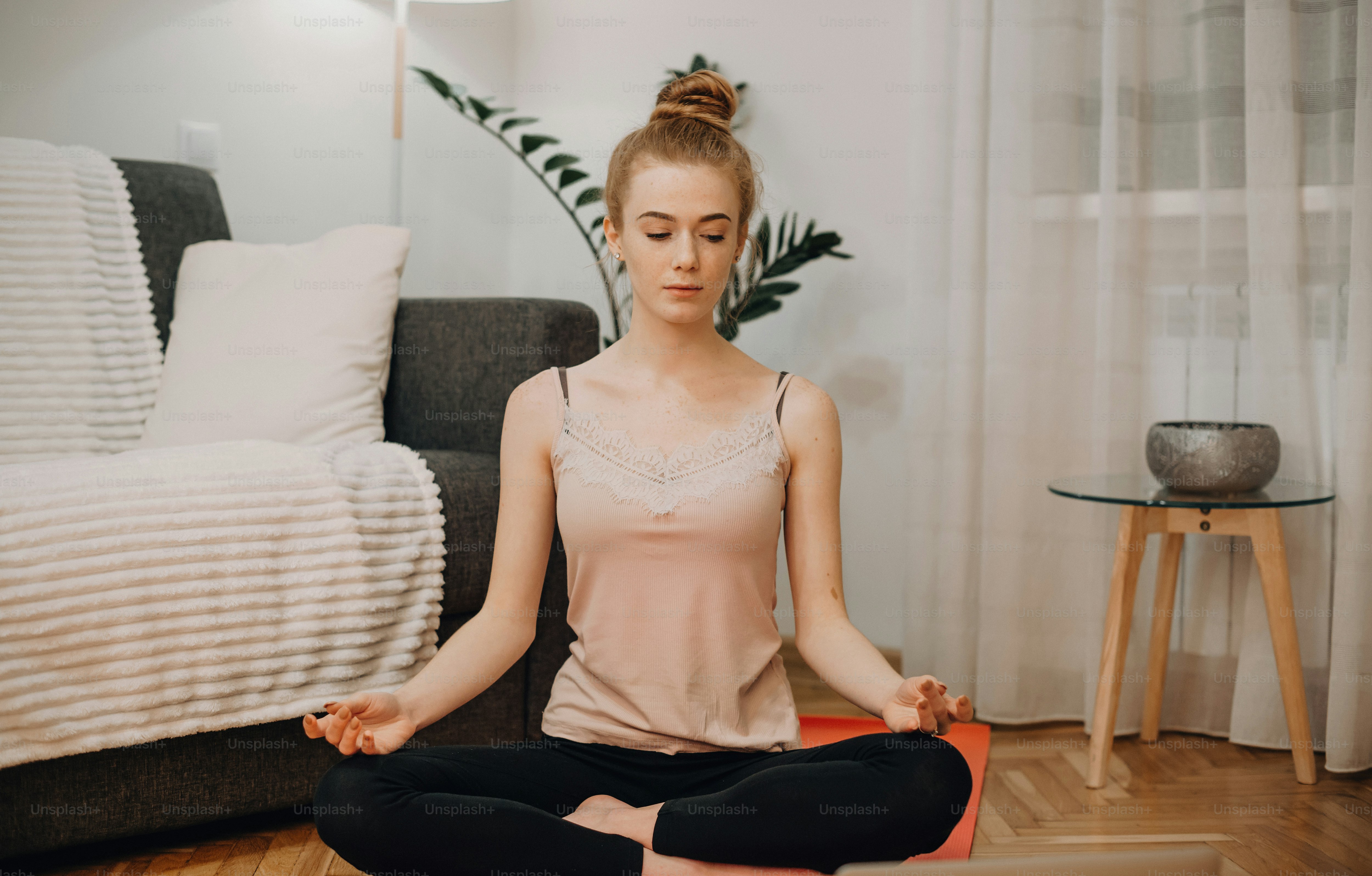 Femme caucasienne aux cheveux roux méditant sur un tapis rouge sur le ...