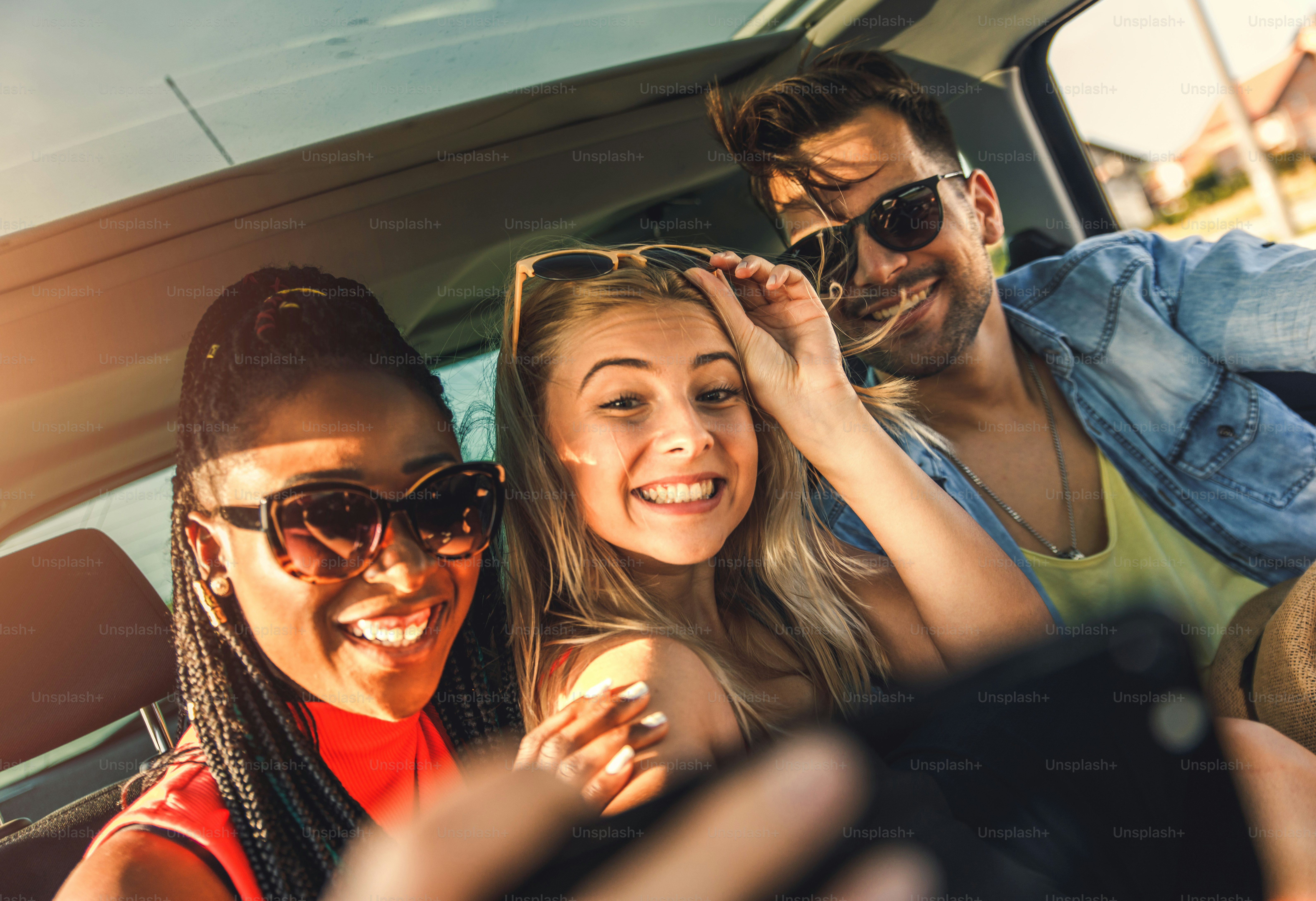 Three best friends enjoying traveling in the car, sitting in rear seat ...
