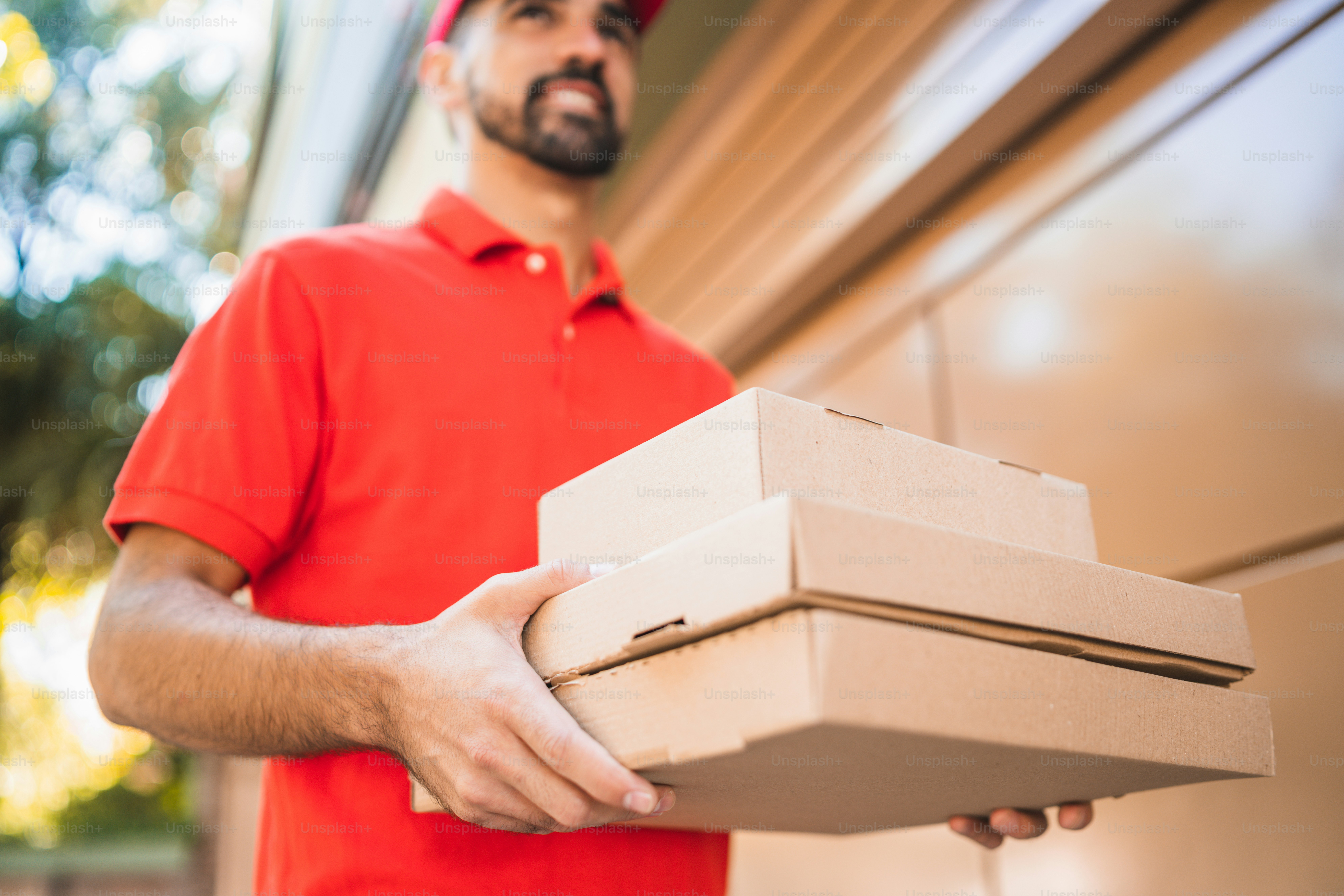 Portrait of a delivery man carrying packages while making home delivery ...