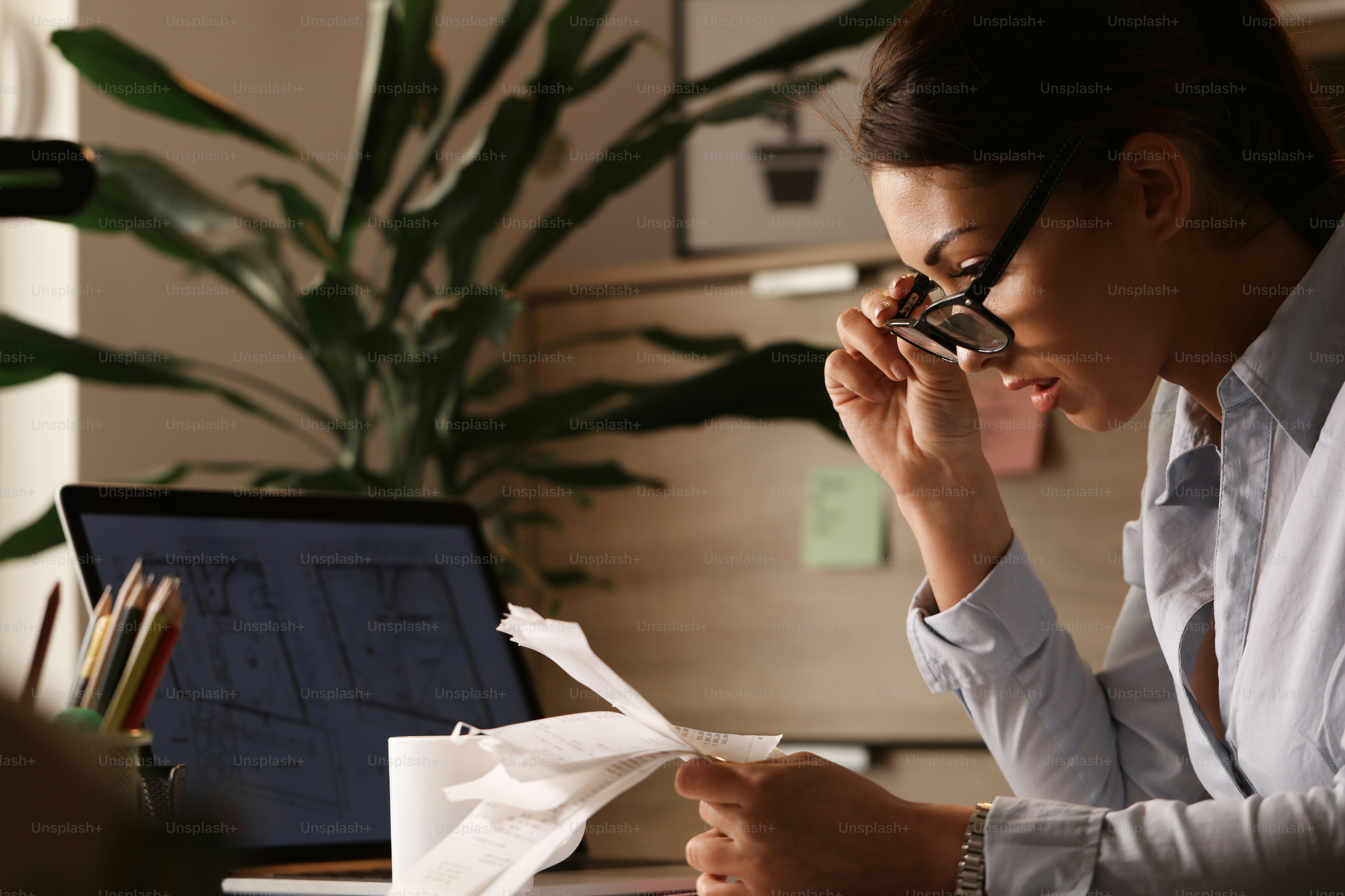 Young female entrepreneur analyzing financial bills while working in ...