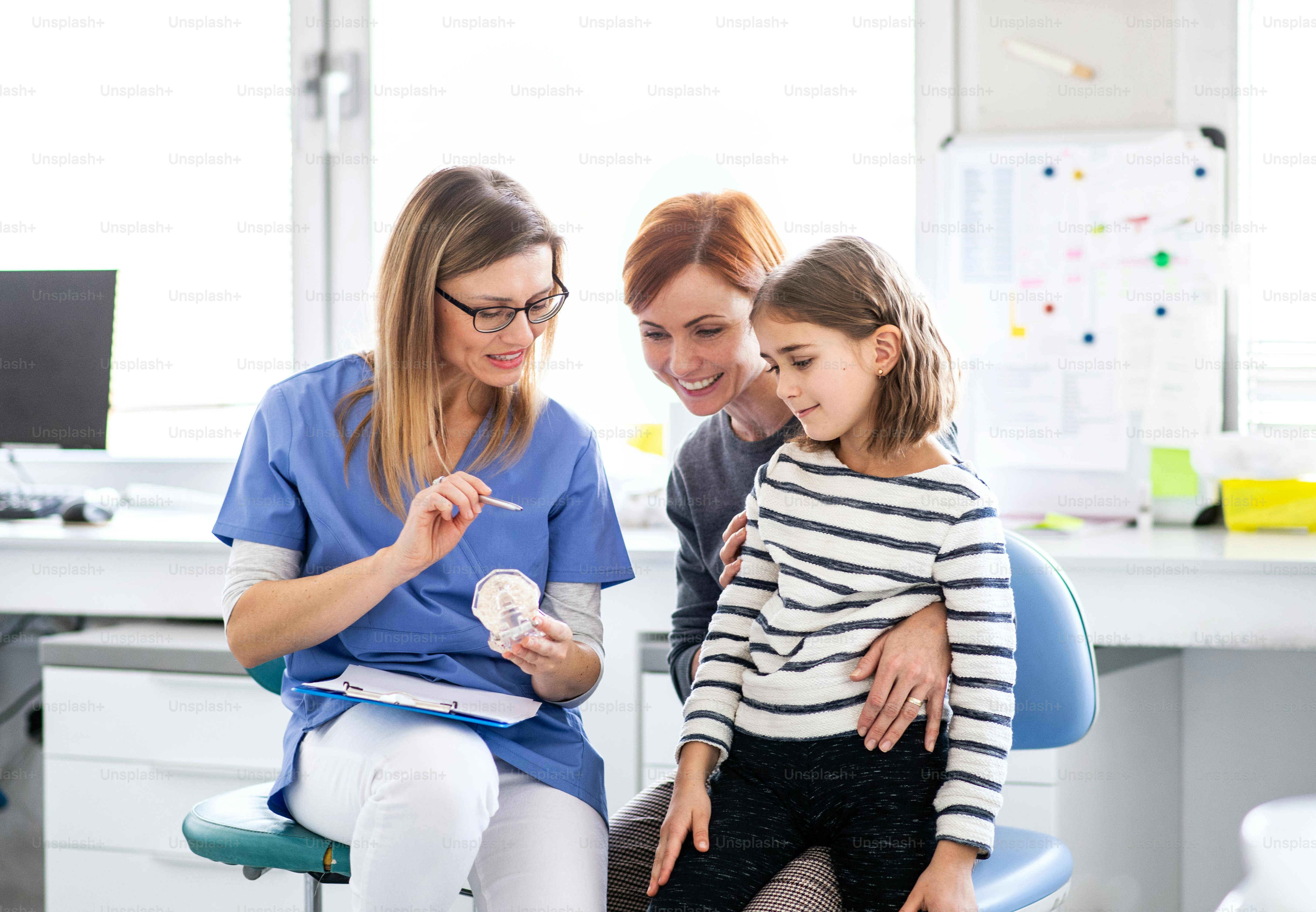 A small girl, mother and dentist in surgery, a dental checkup. photo ...