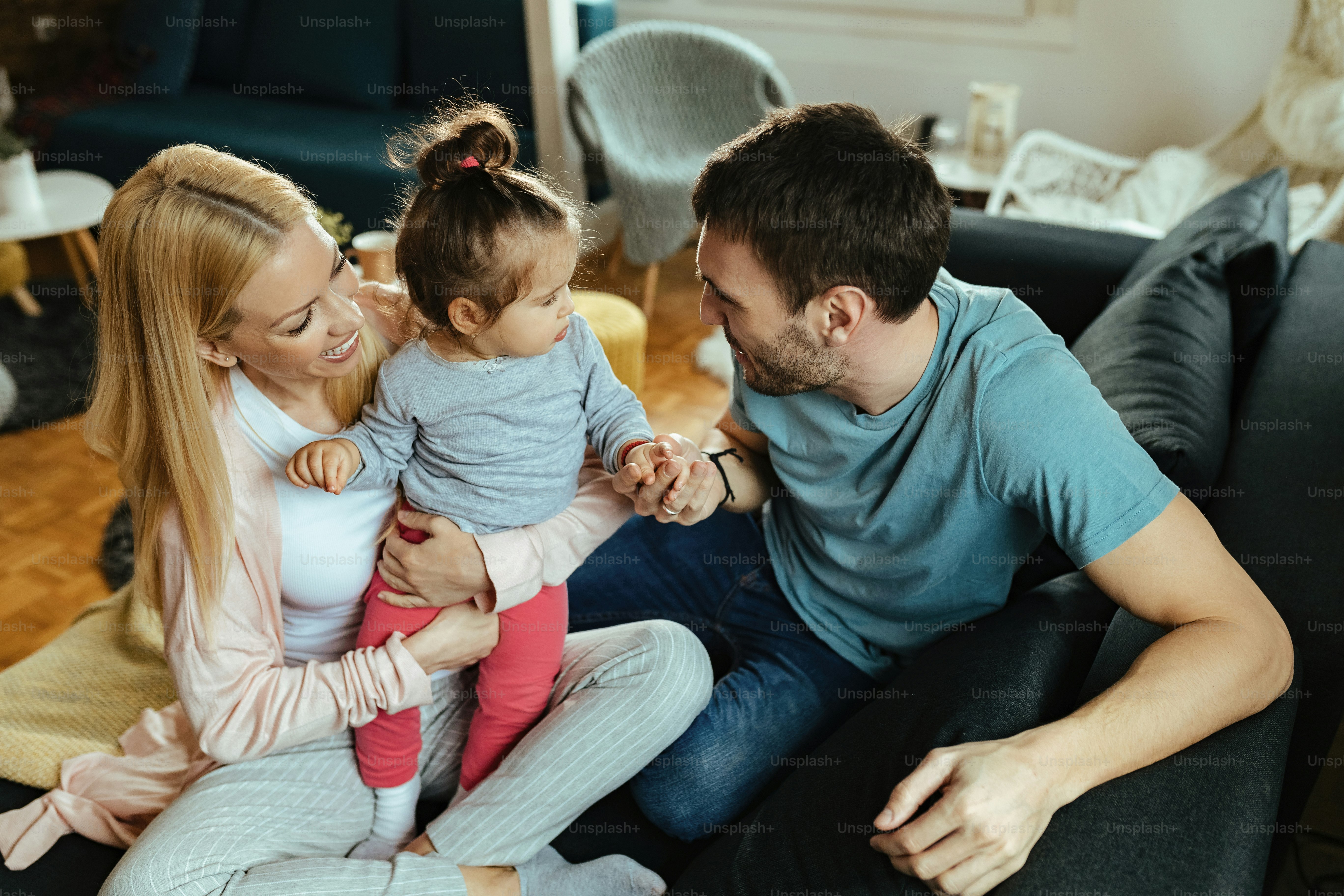 Happy parents having fun with their small daughter while talking to her ...
