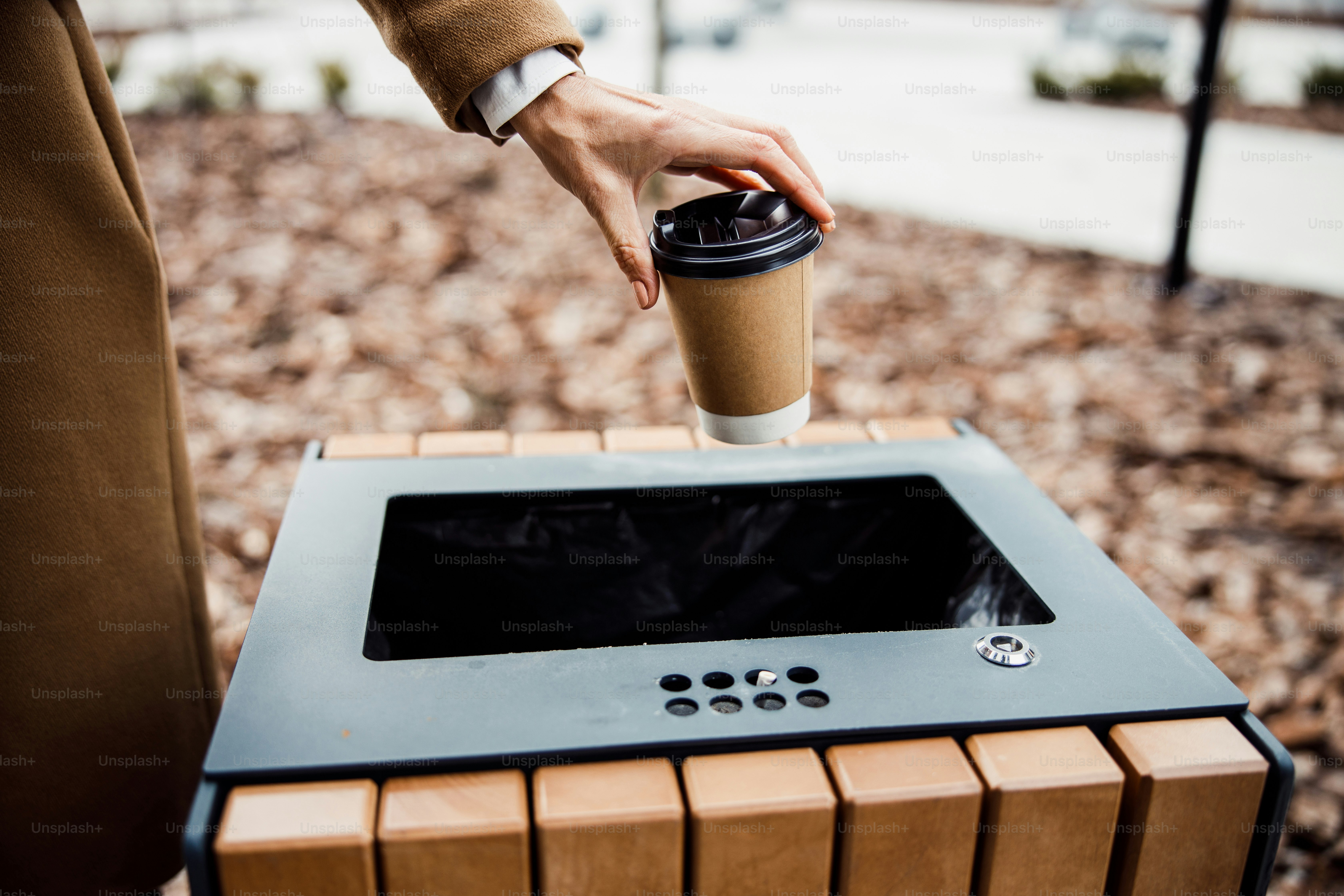 Cropped photo of a female holding an empty paper cup over an outdoor ...