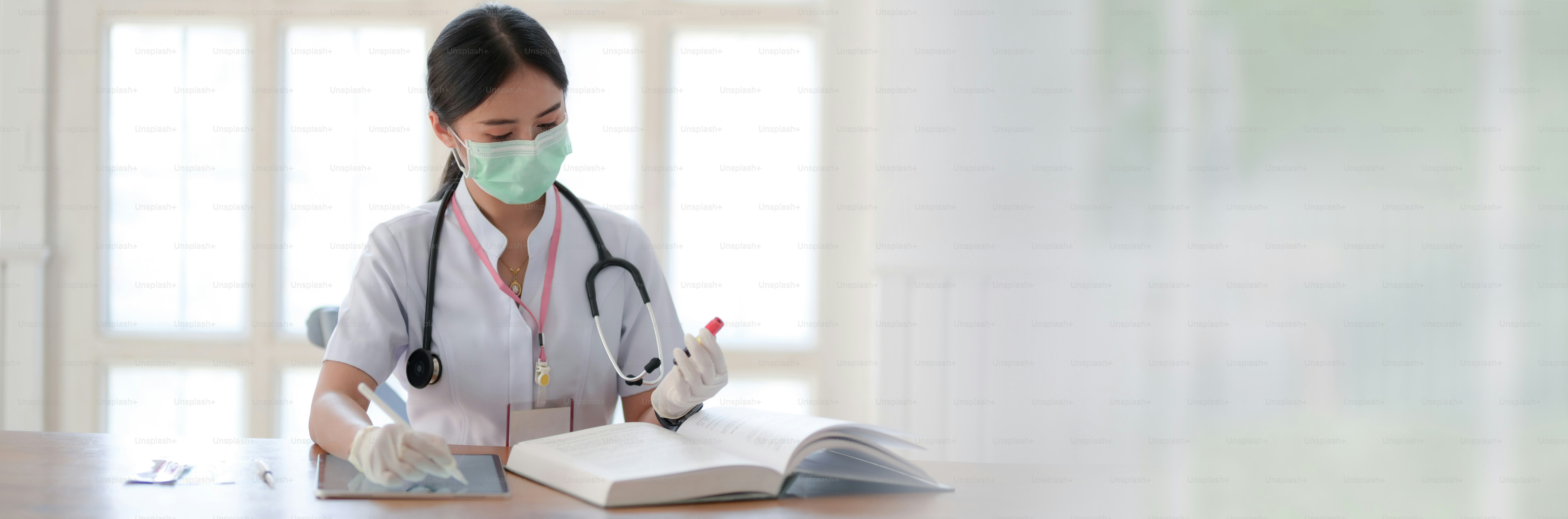 Cropped shot of female doctor reading book to analyse blood test while ...