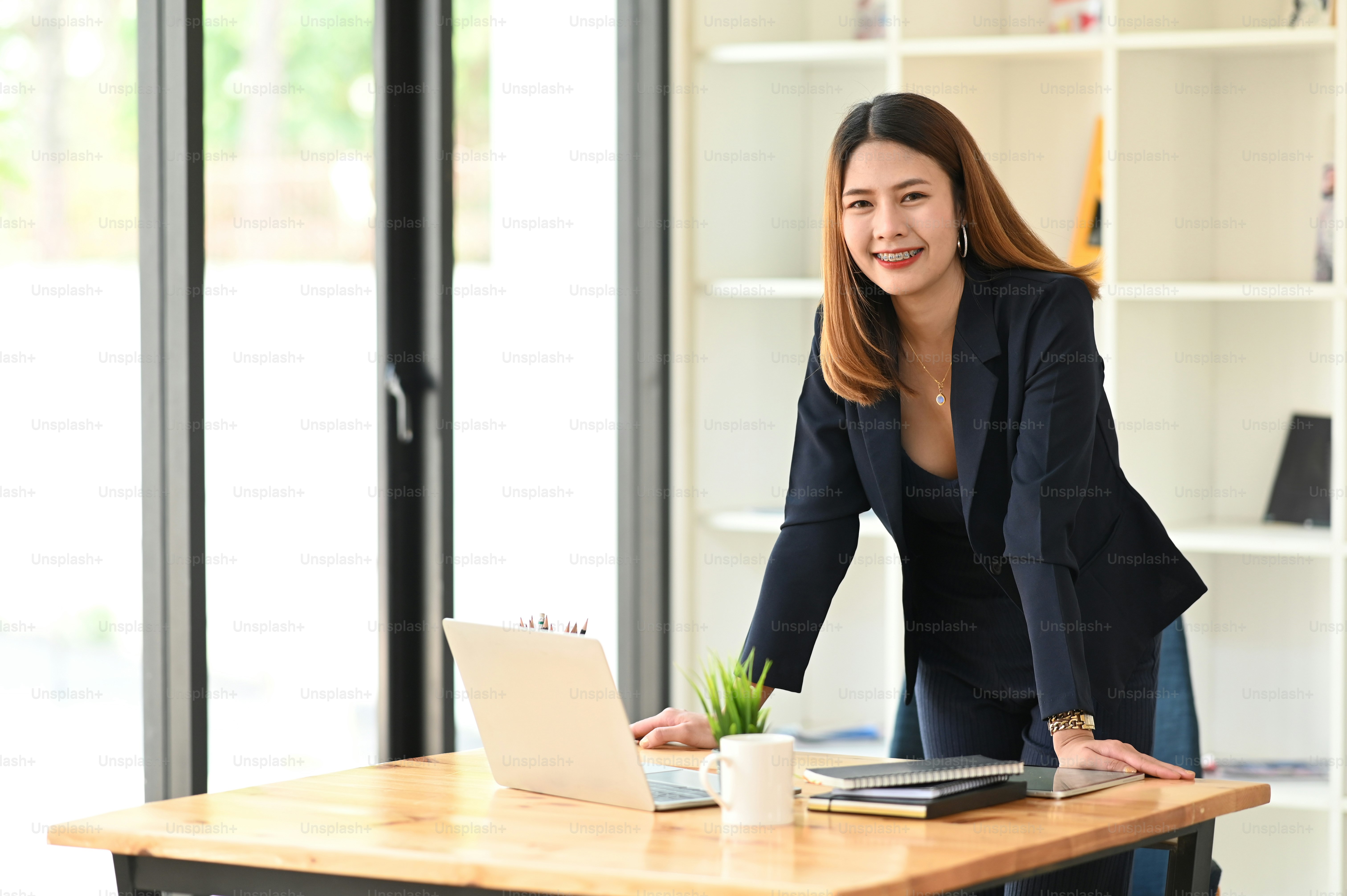 Photo of beautiful businesswoman standing up at her wooden working desk ...