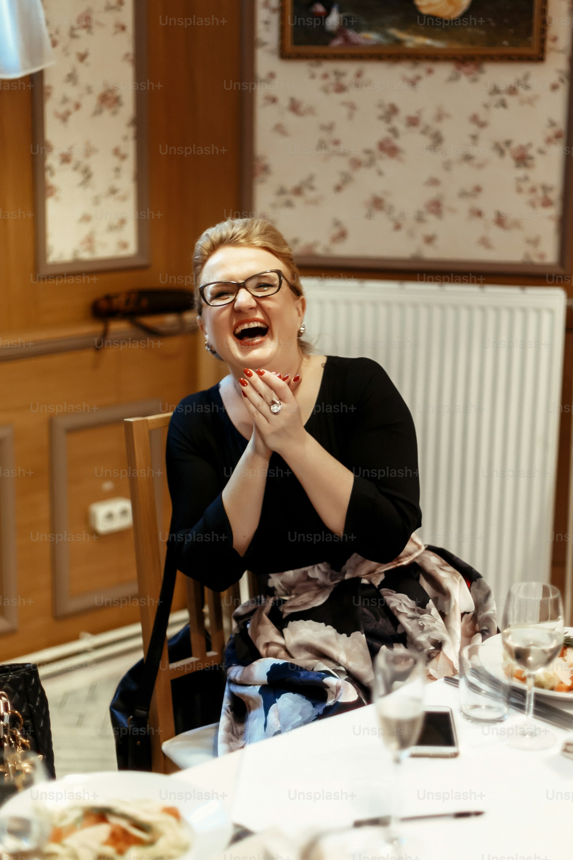 Happy stylish woman in glasses laughing at celebration in restaurant ...