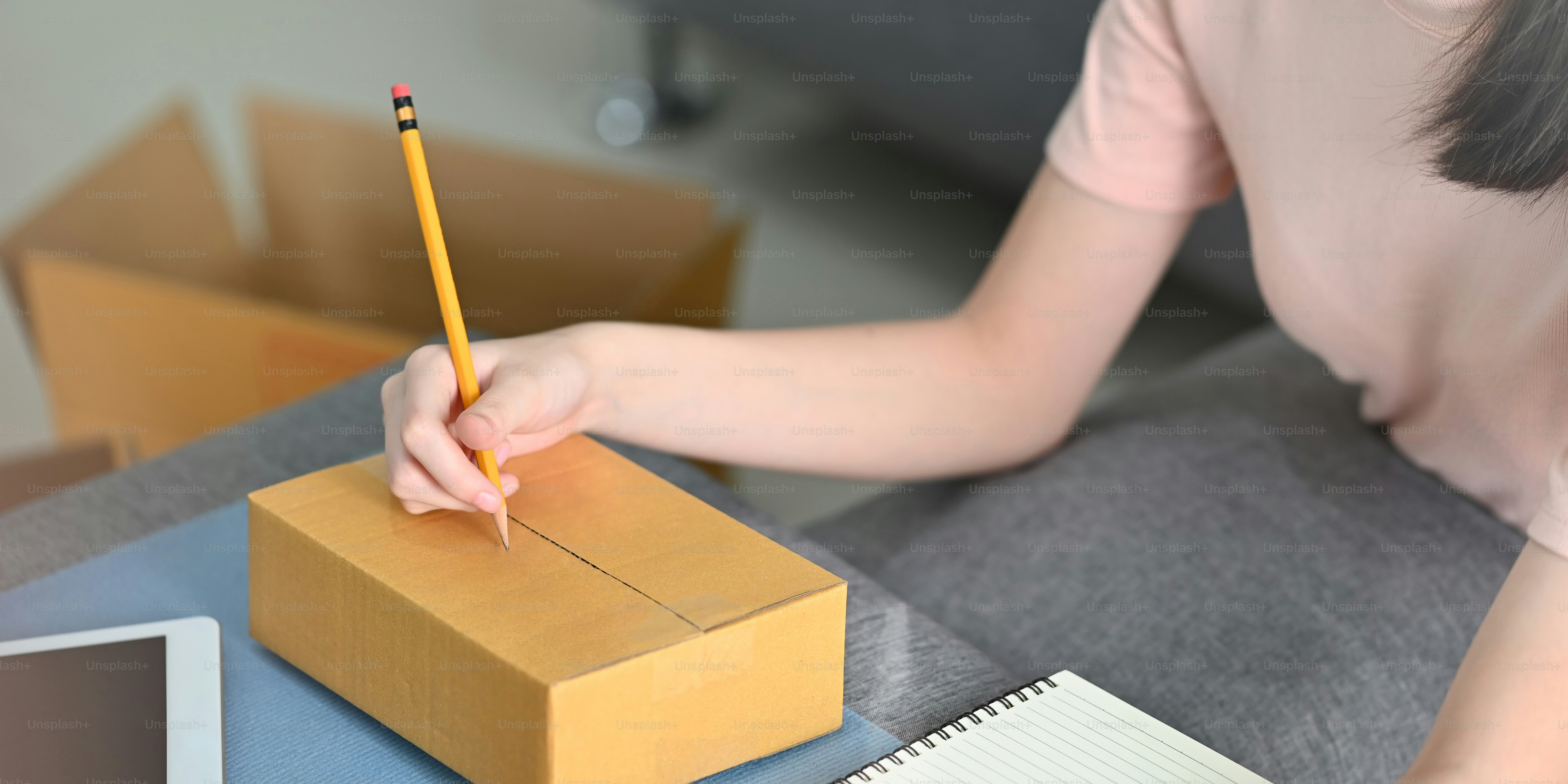 Closeup woman addressing/writing address on cardboard box while sitting ...
