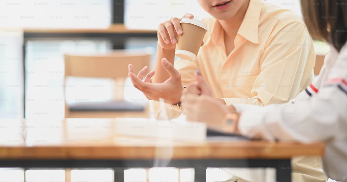 문서 파일을 들고 잘린 젊은 부부는 작업을 마친 후 휴식을 취하고 편안한 카페를 배경으로 나무 작업 책상에 함께 앉아 있습니다