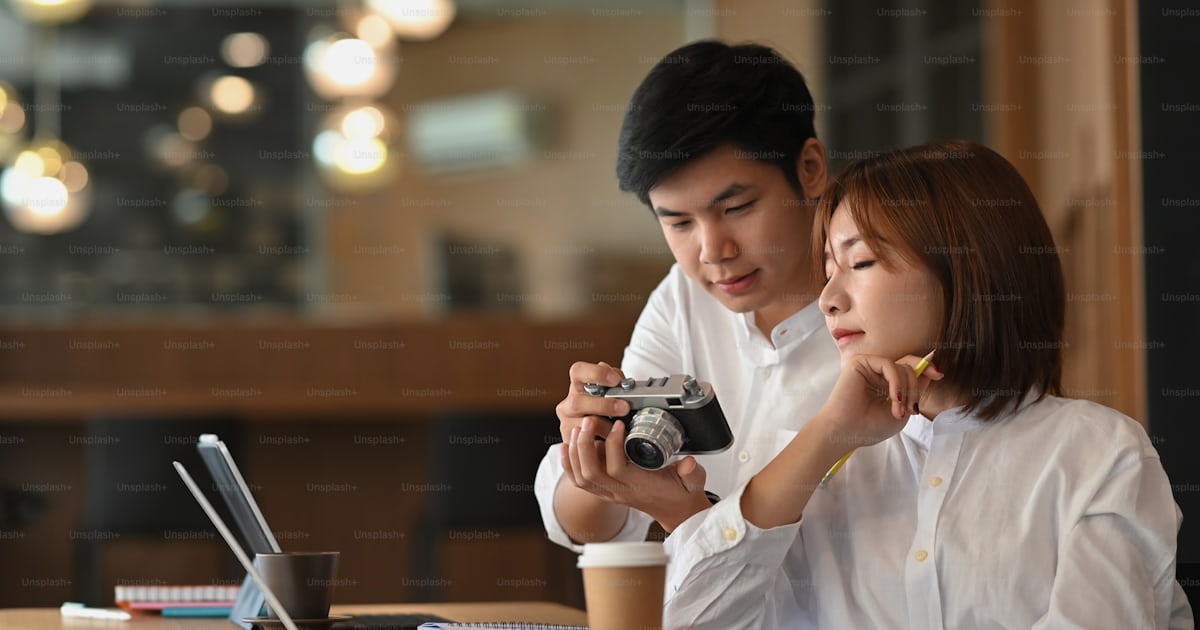 편안한 카페를 배경으로 나무 작업 책상에 앉아 컴퓨터 노트북과 문서를 가지고 함께 일하는 젊은 부부의 사진 사진