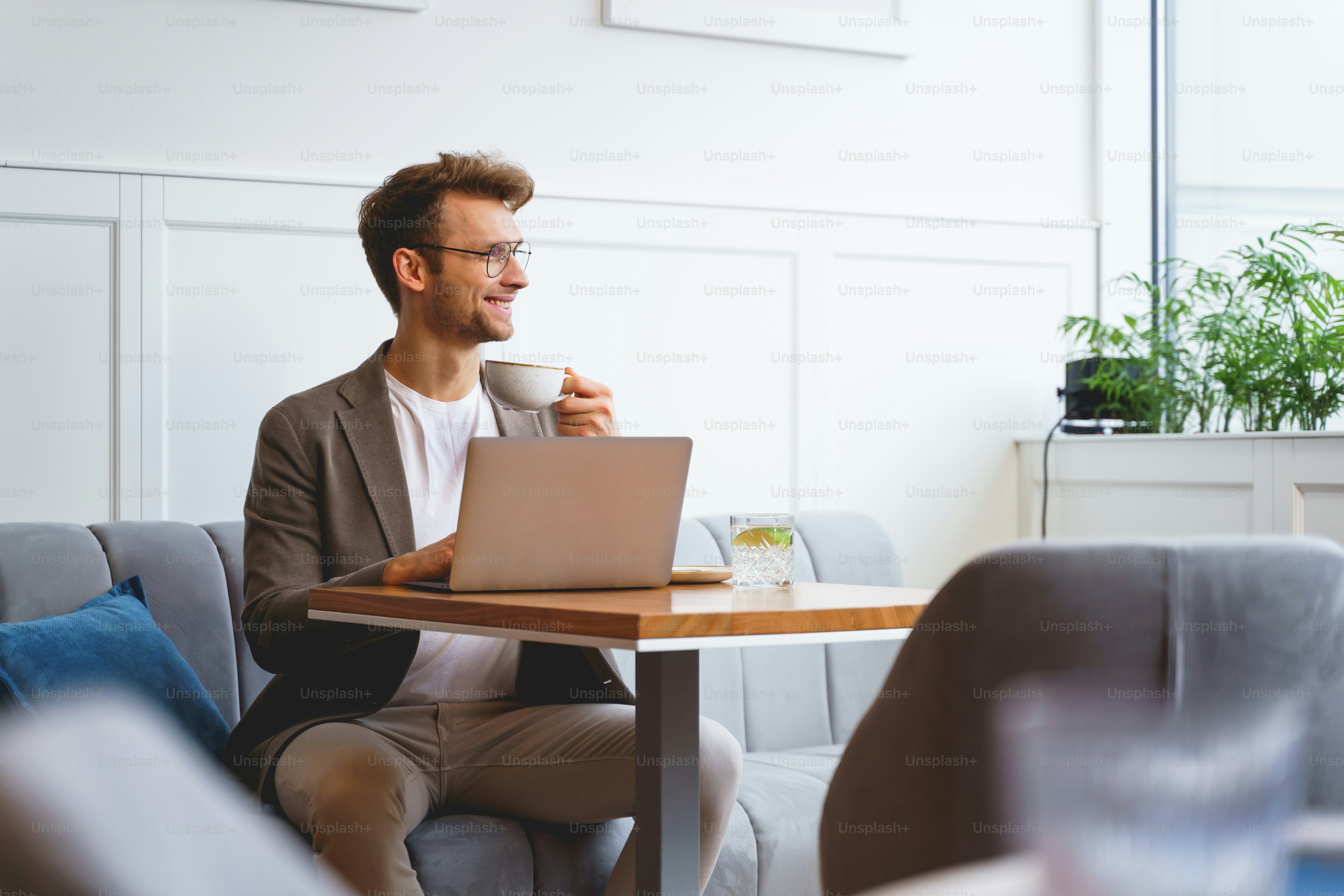 Handsome gentleman holding cup of hot drink and smiling while sitting ...