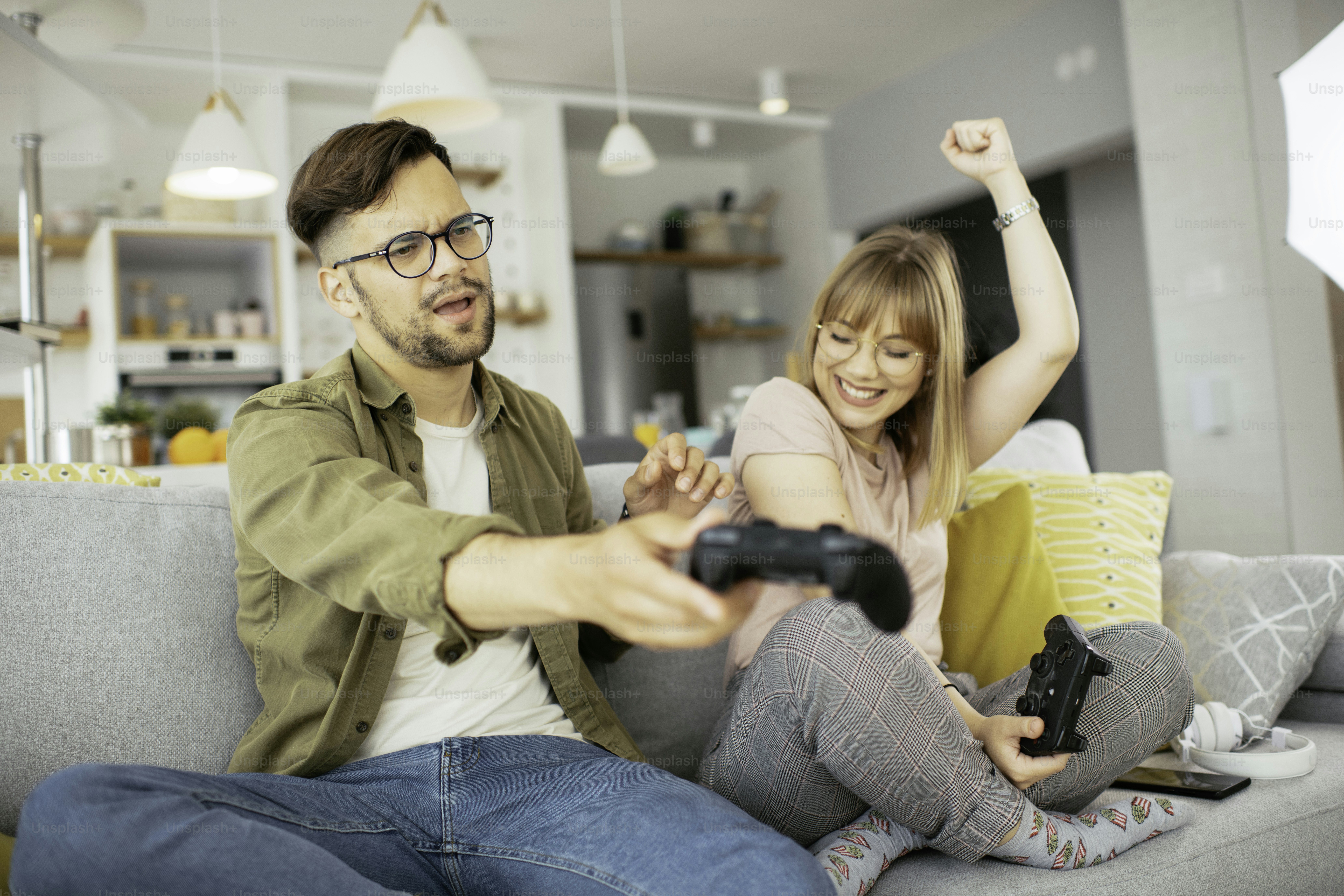 Boyfriend and girlfriend playing video game with joysticks in living ...