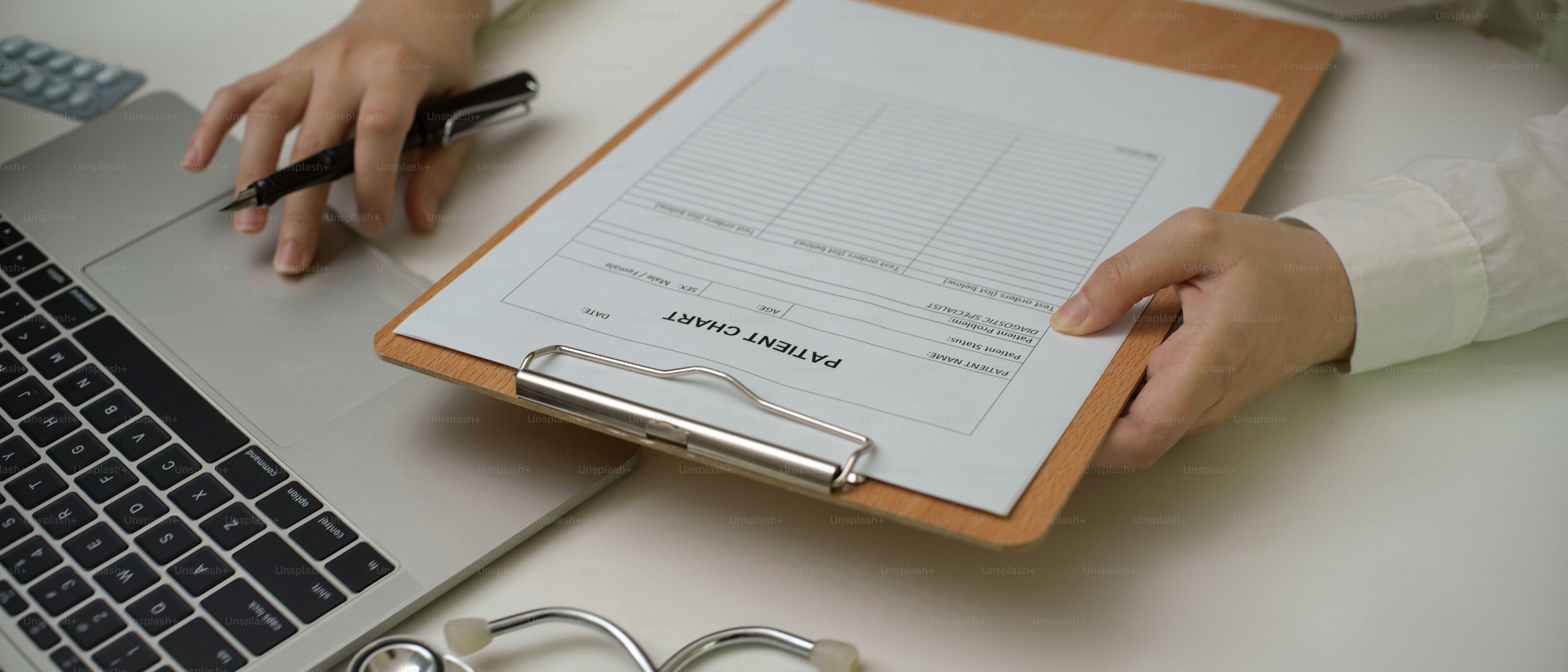 Close up view of doctor working with laptop, patient chart and ...