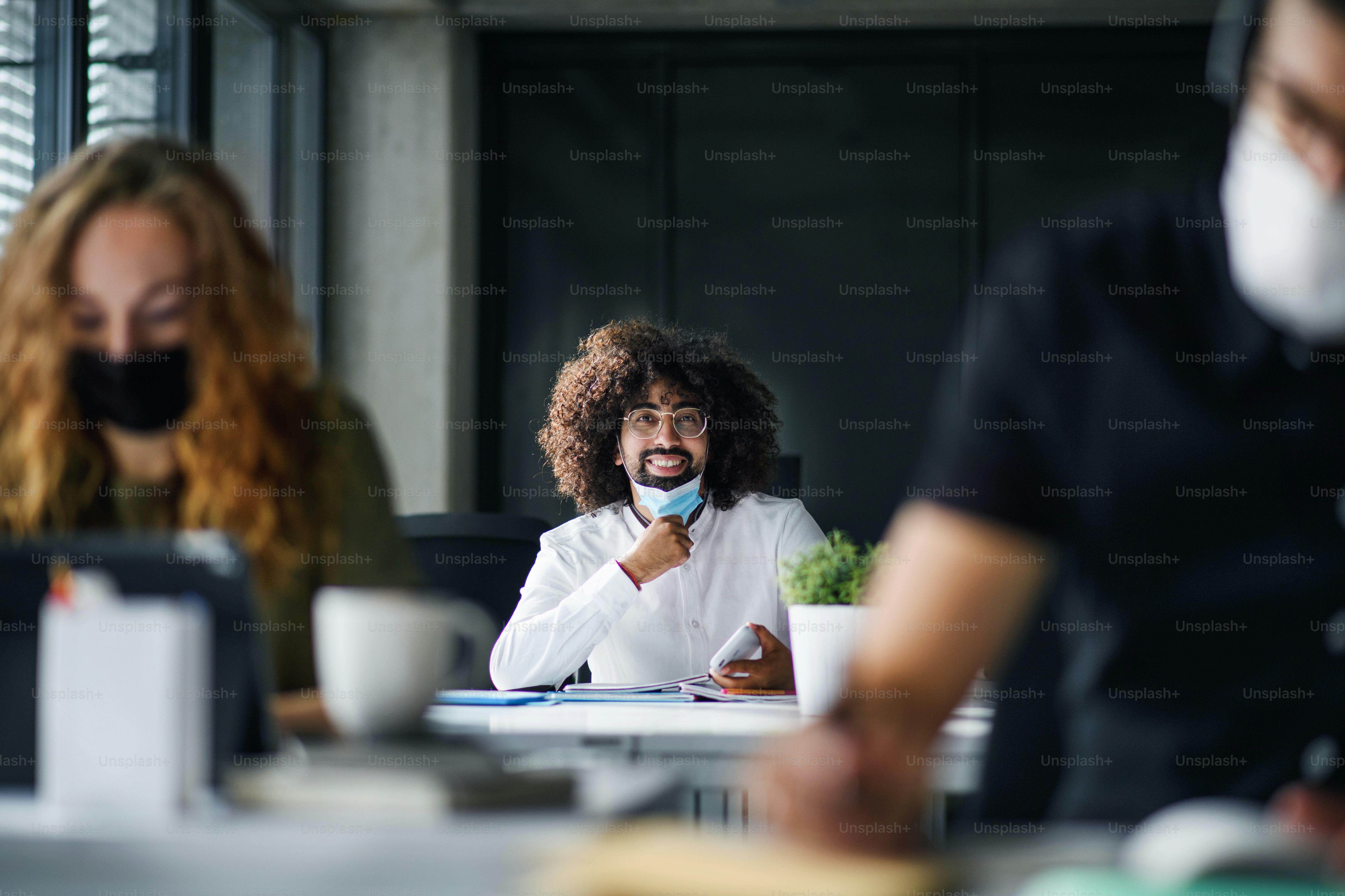 Young people with face masks back at work in office after coronavirus ...