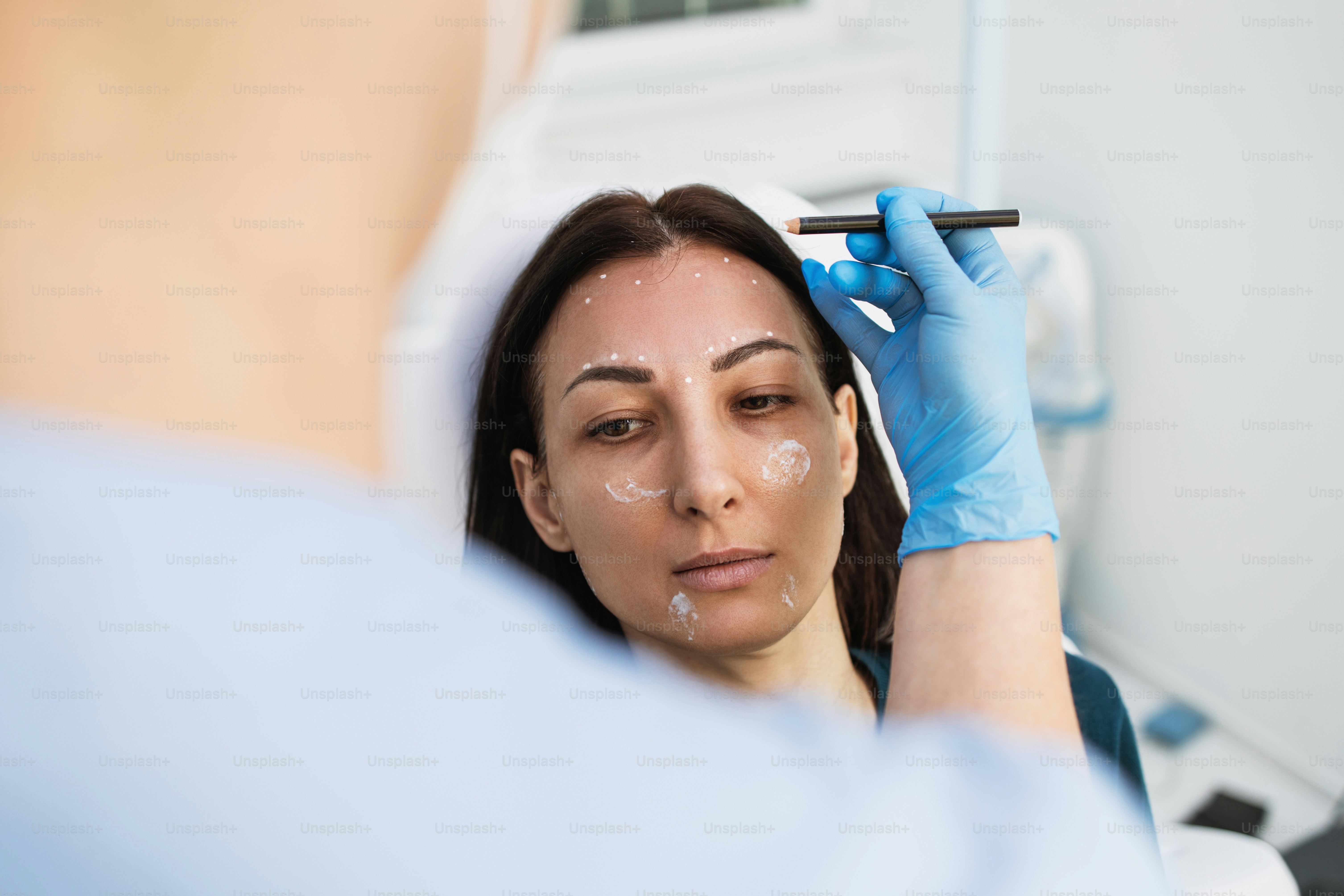 Beautiful young female patient with correction lines and dots on the ...