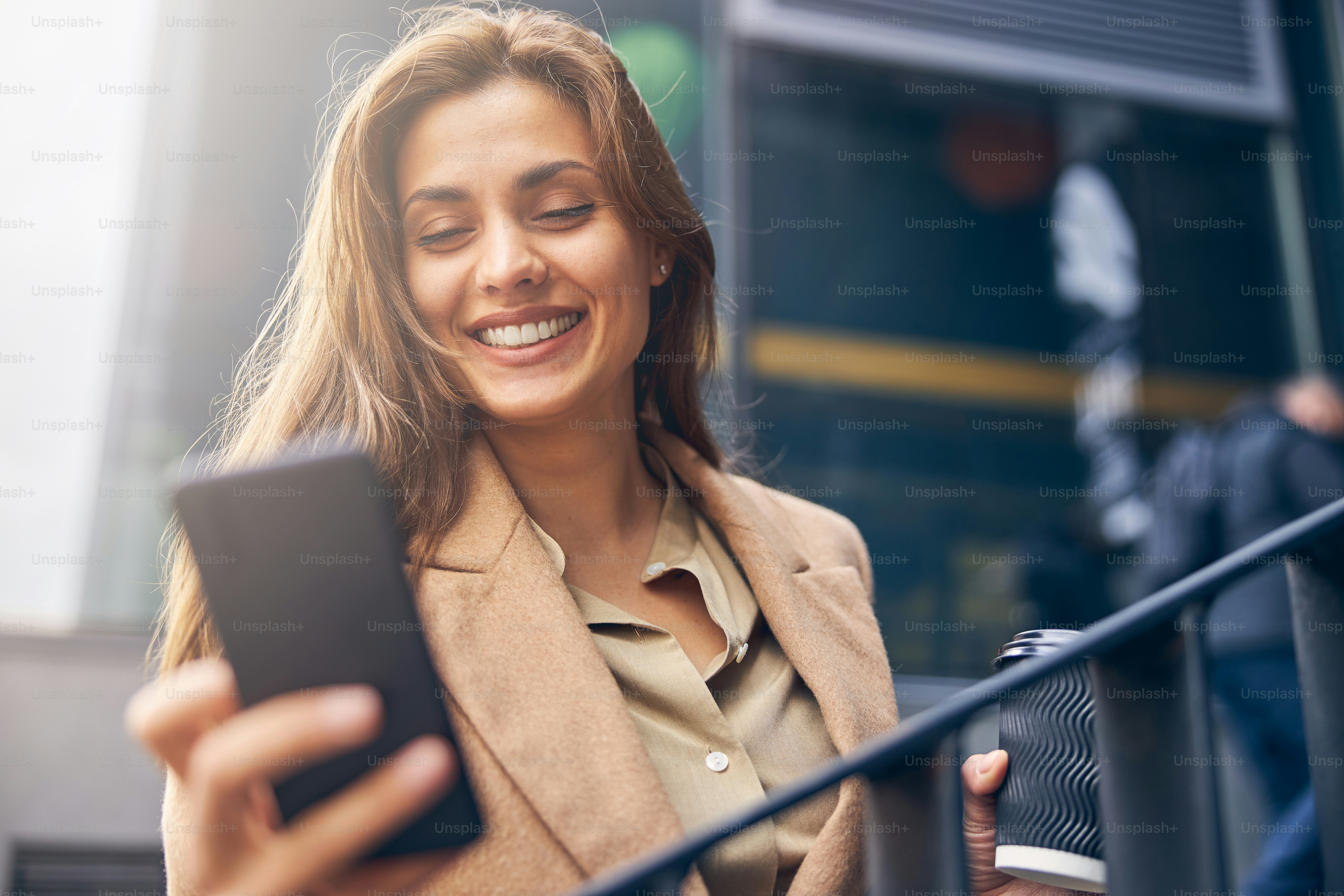 Portrait of a smiling pleased lovely lady staring at the mobile phone ...
