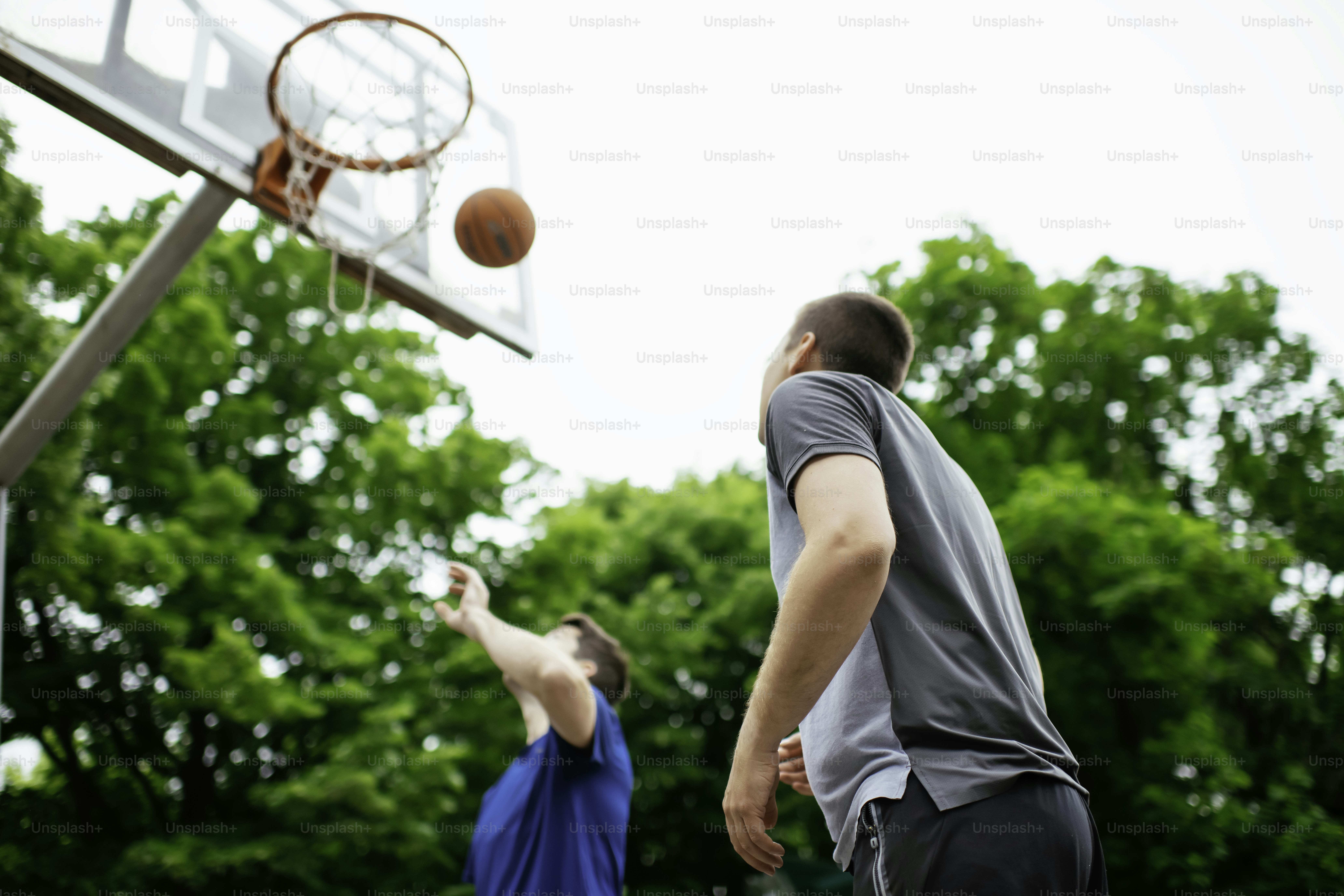 Two young men playing basketball in the park. Friends having a friendly ...
