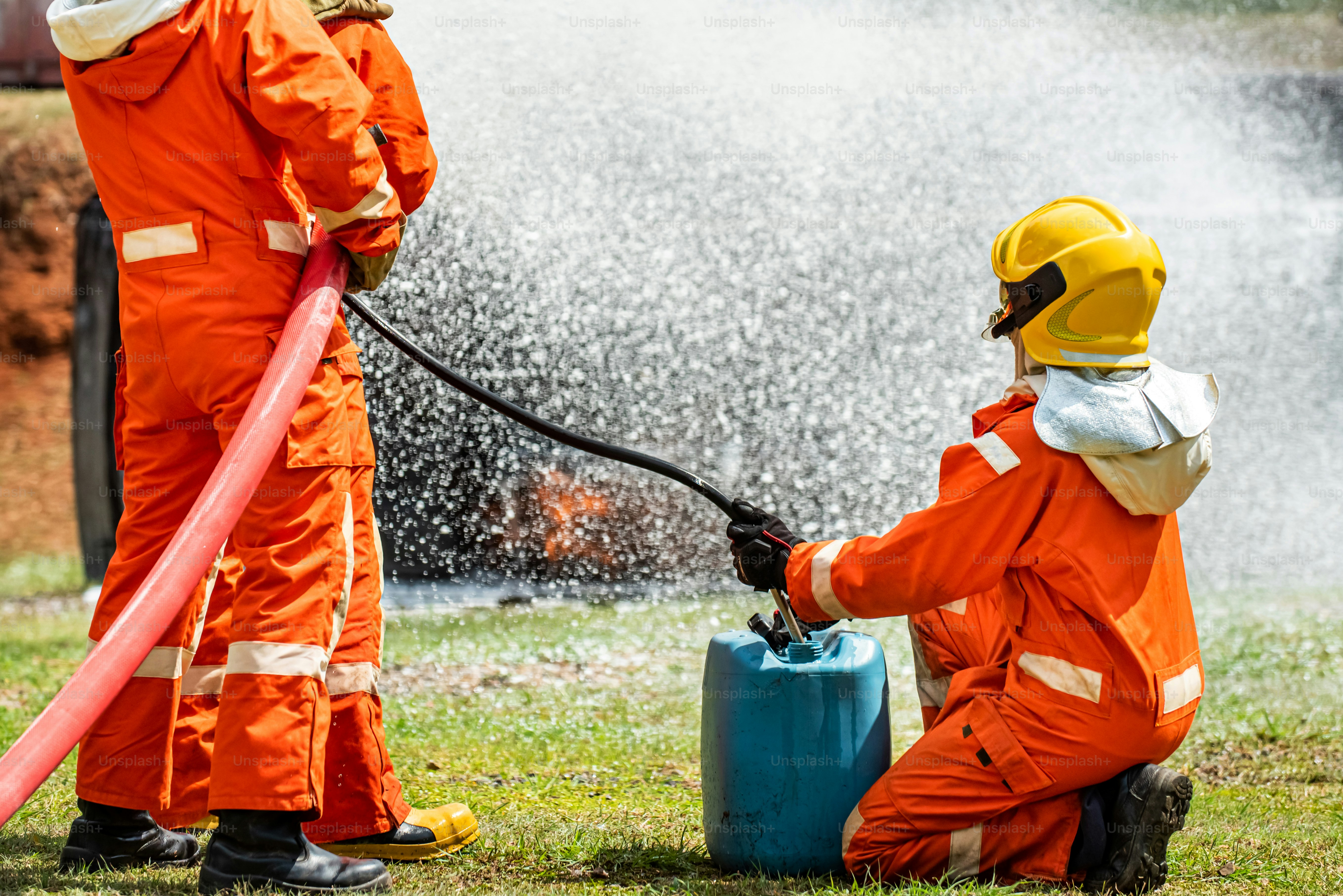 Group of firefighter teamwork using water and chemical foam spraying ...