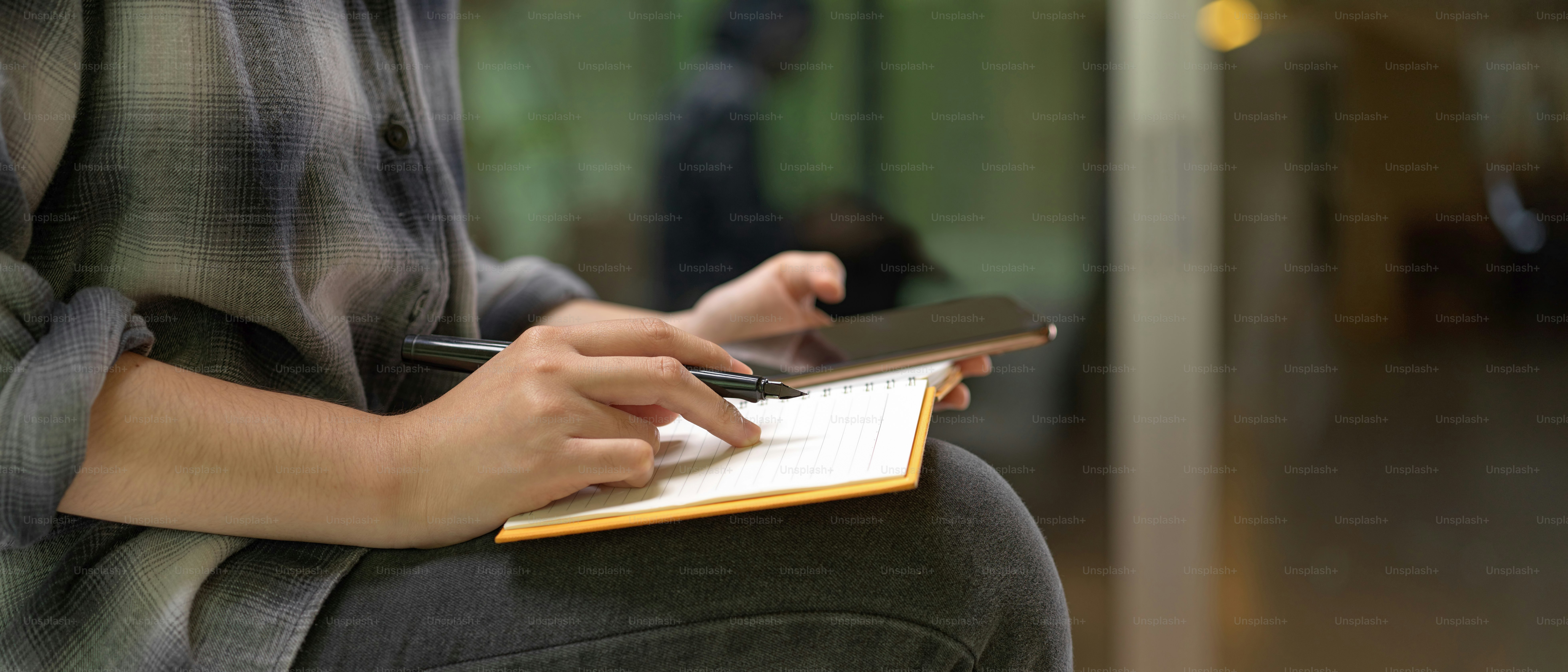 Side view of female worker sitting on worktable and taking note on ...