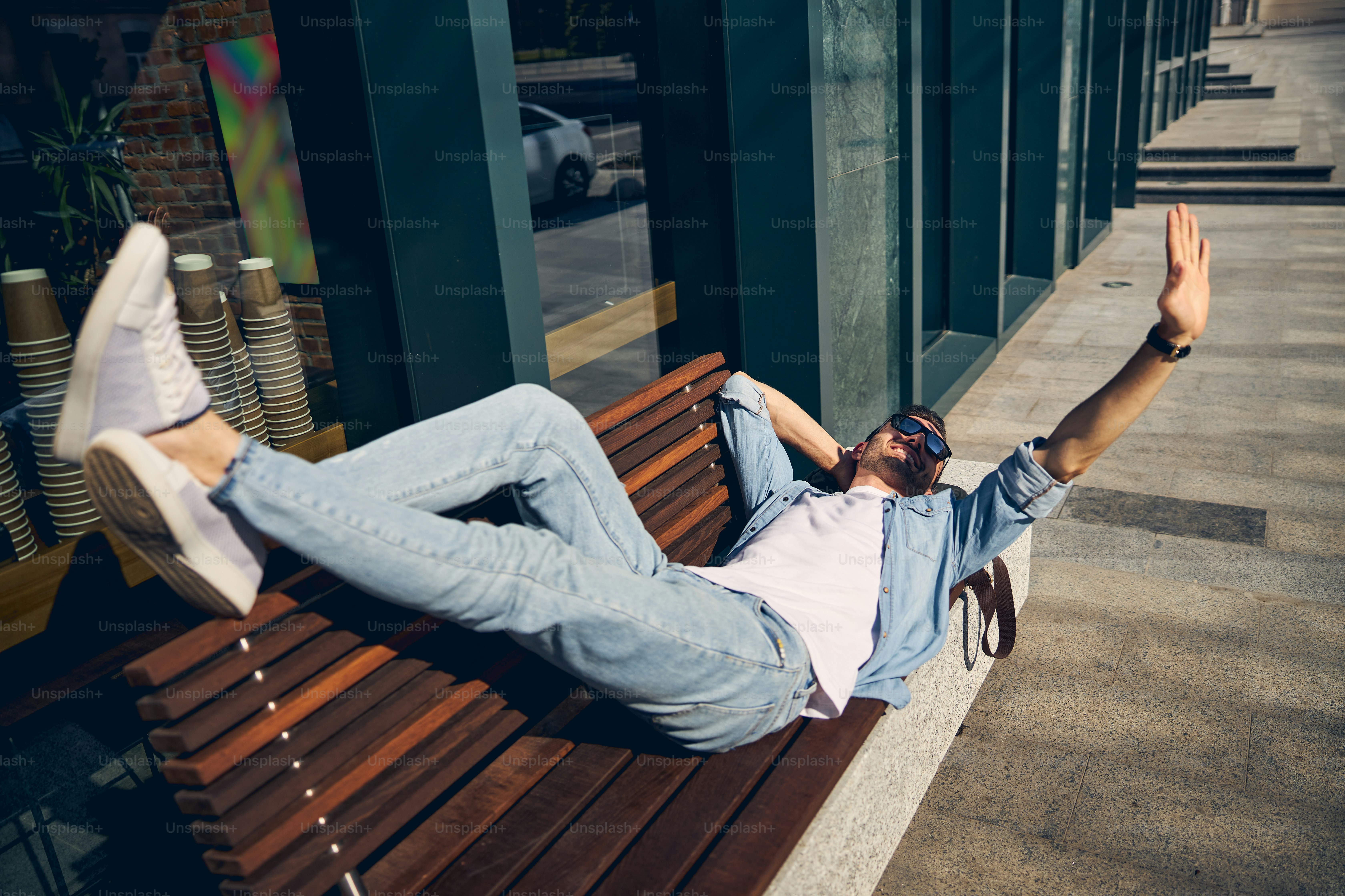 Joyful man raising his arm while making shadow during having rest on ...