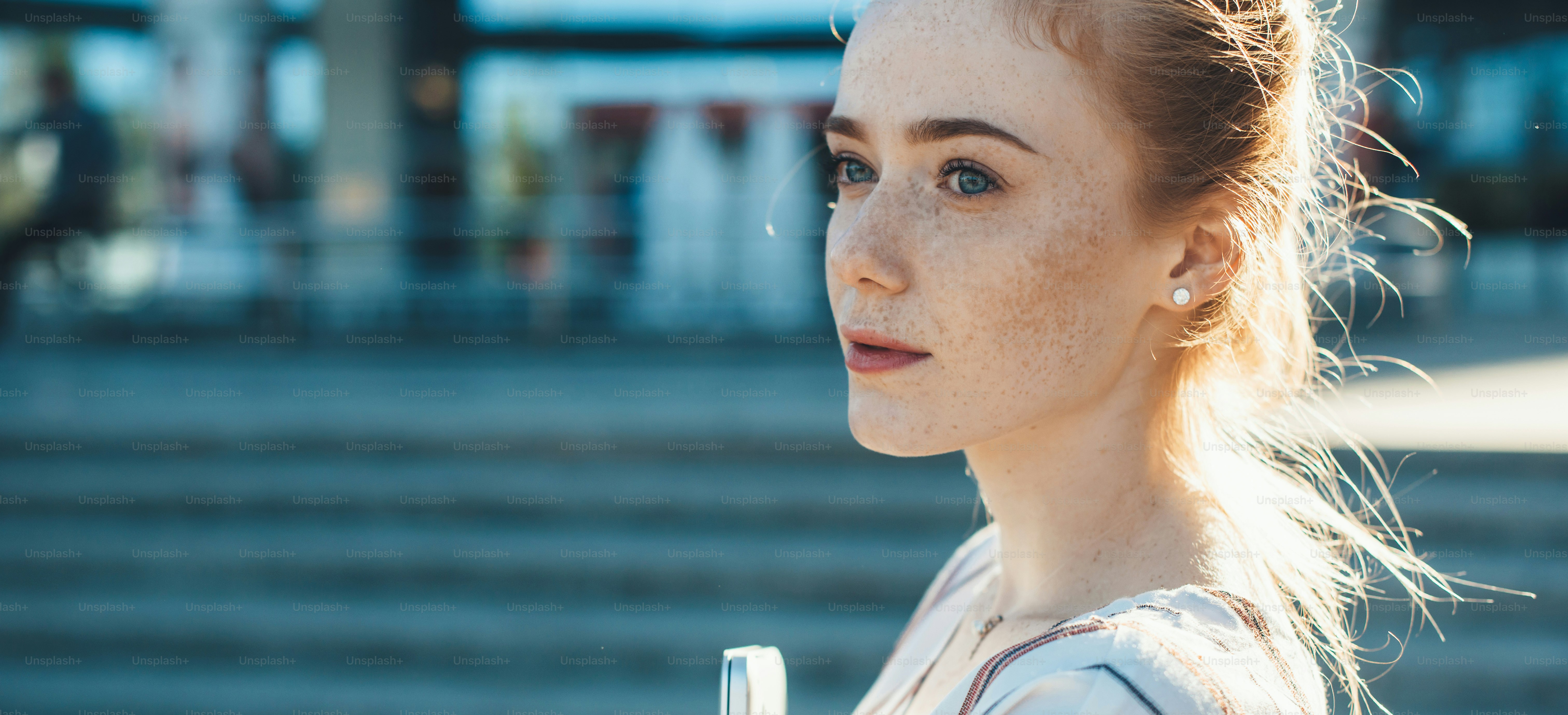 Freckled lady with red hair looking away while posing outside with a ...