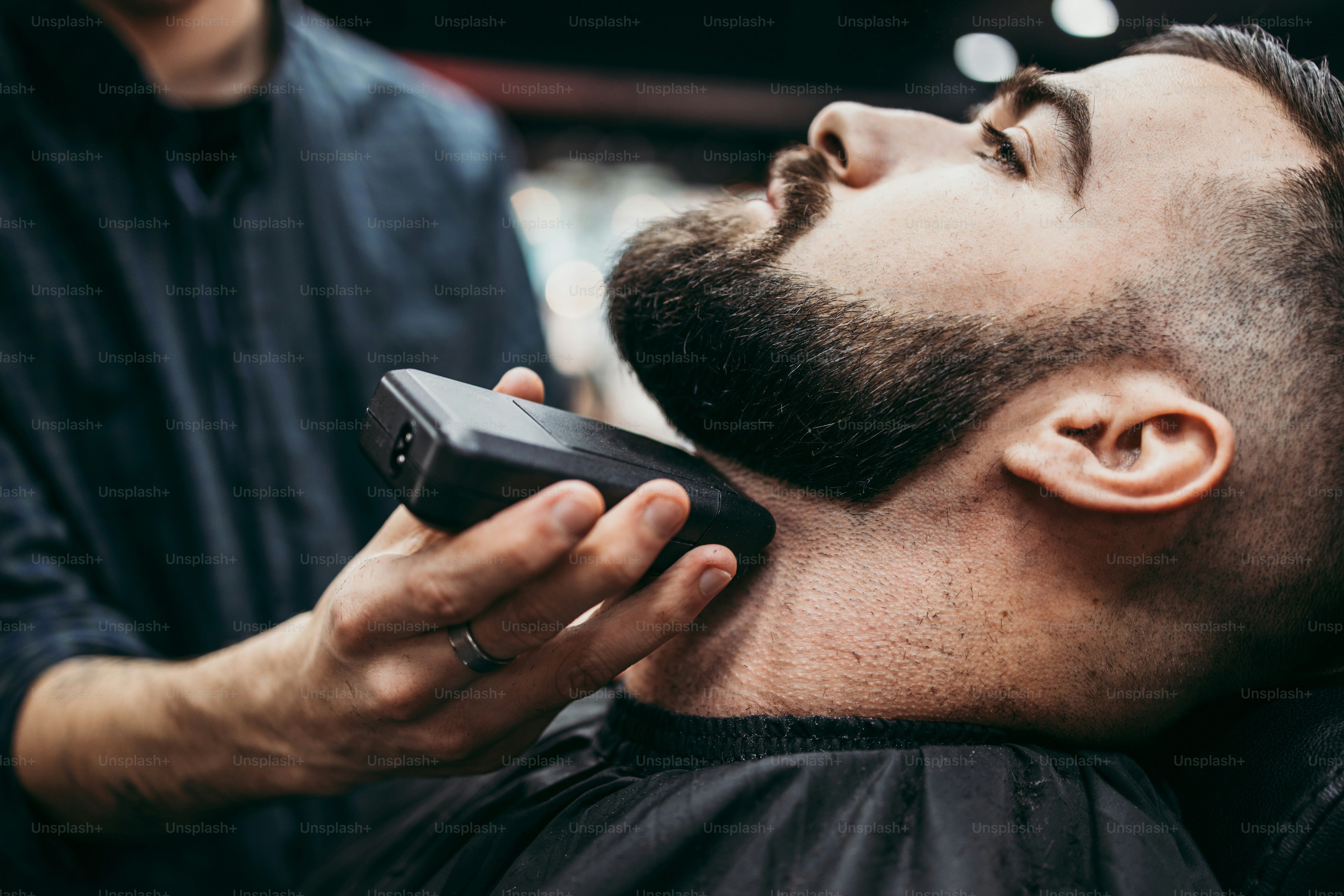 Good looking young adult man getting a hair and beard styling and ...