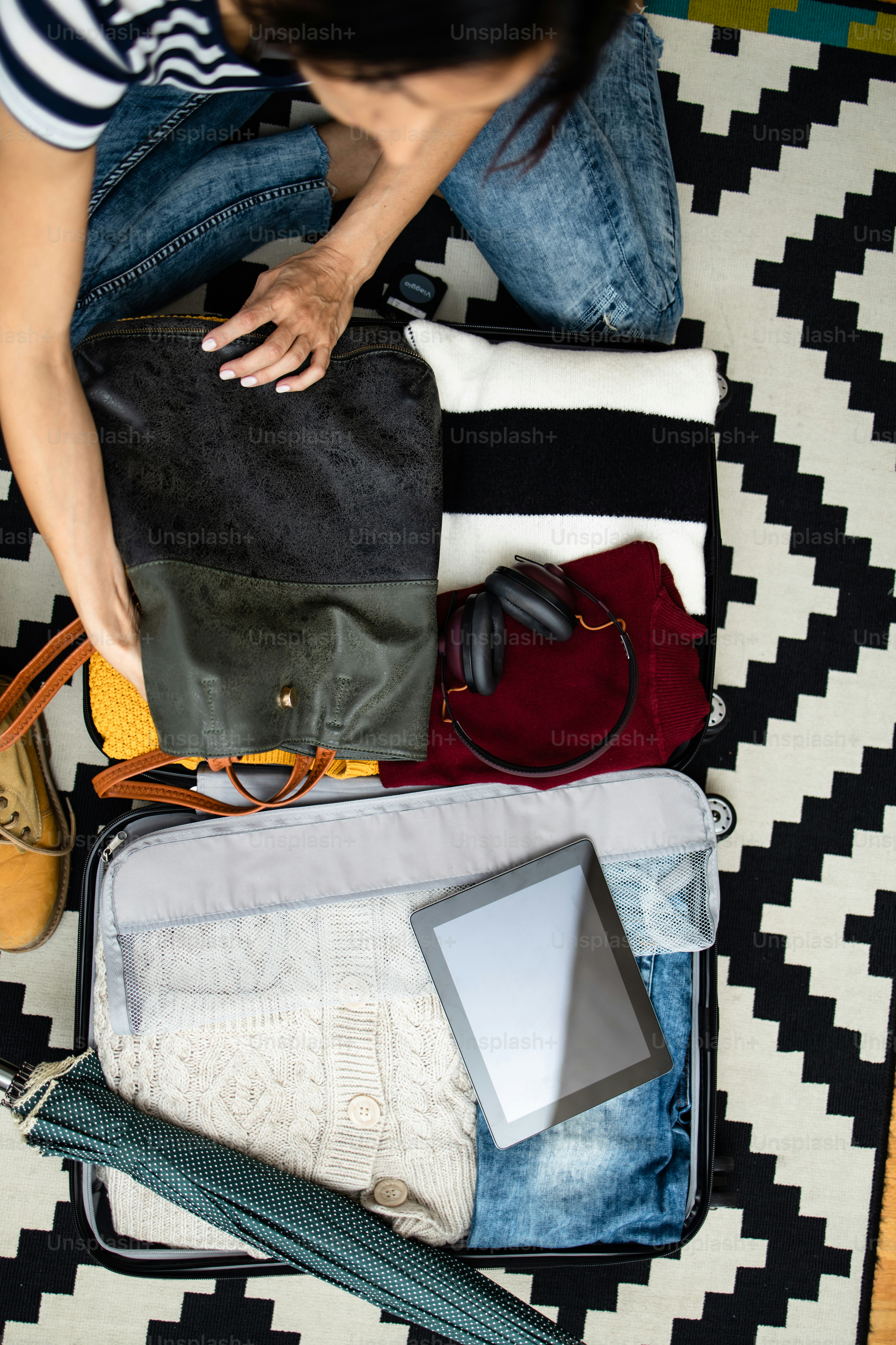 Young woman tourist packing her winter and autumn warm stuff into a big ...