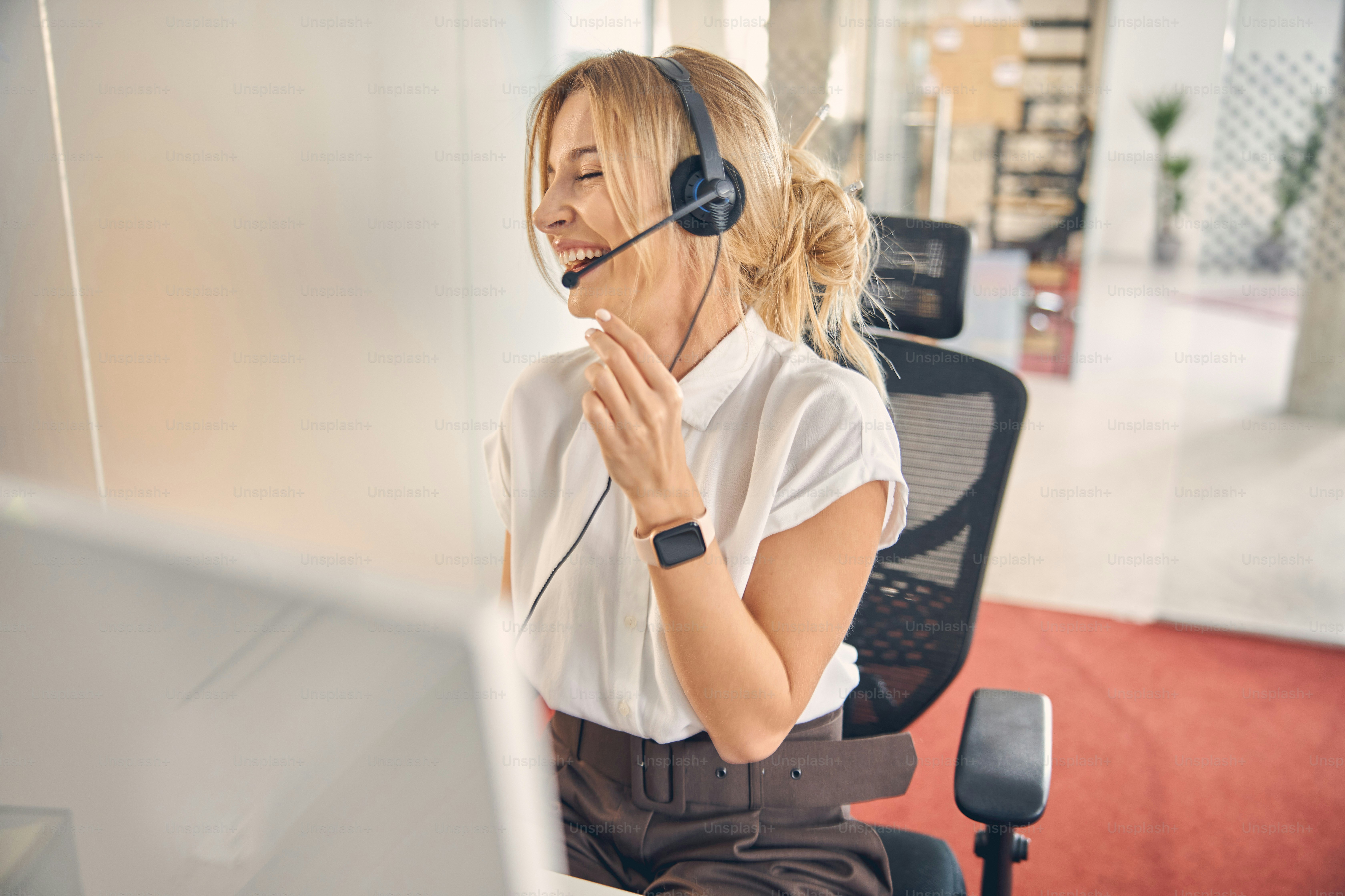 Cheerful female customer service operator sitting at the table with ...