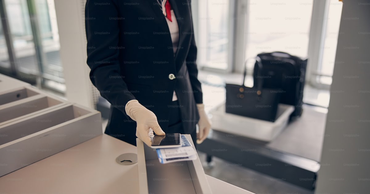 공항 체크인 카운터에 서 있는 동안 탑승권 여권 휴대폰을 들고 멸균 장갑을 낀 여성의 손을 닫습니다 사진