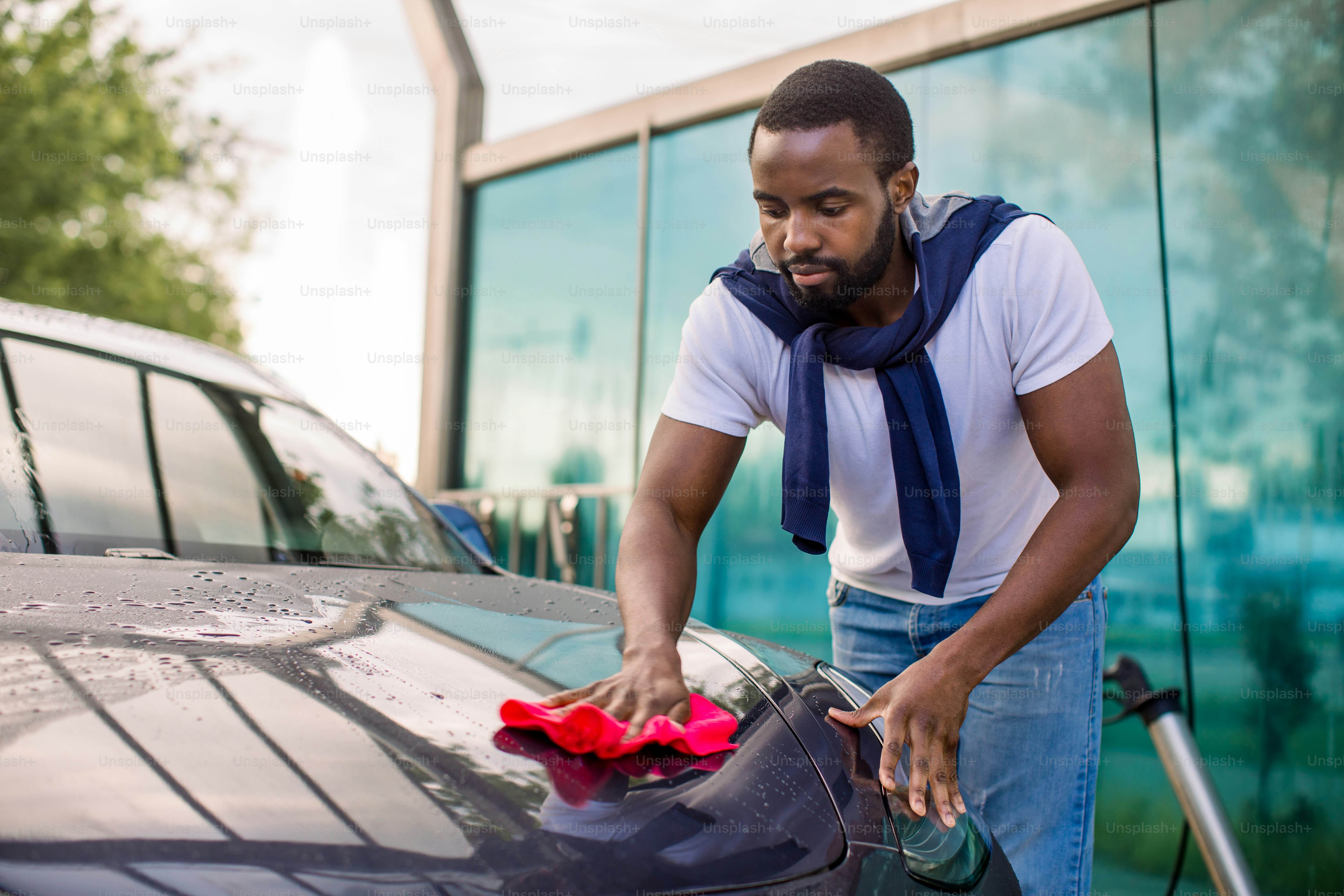 Hands of African man holding green sponge, washing car wheel with foam ...