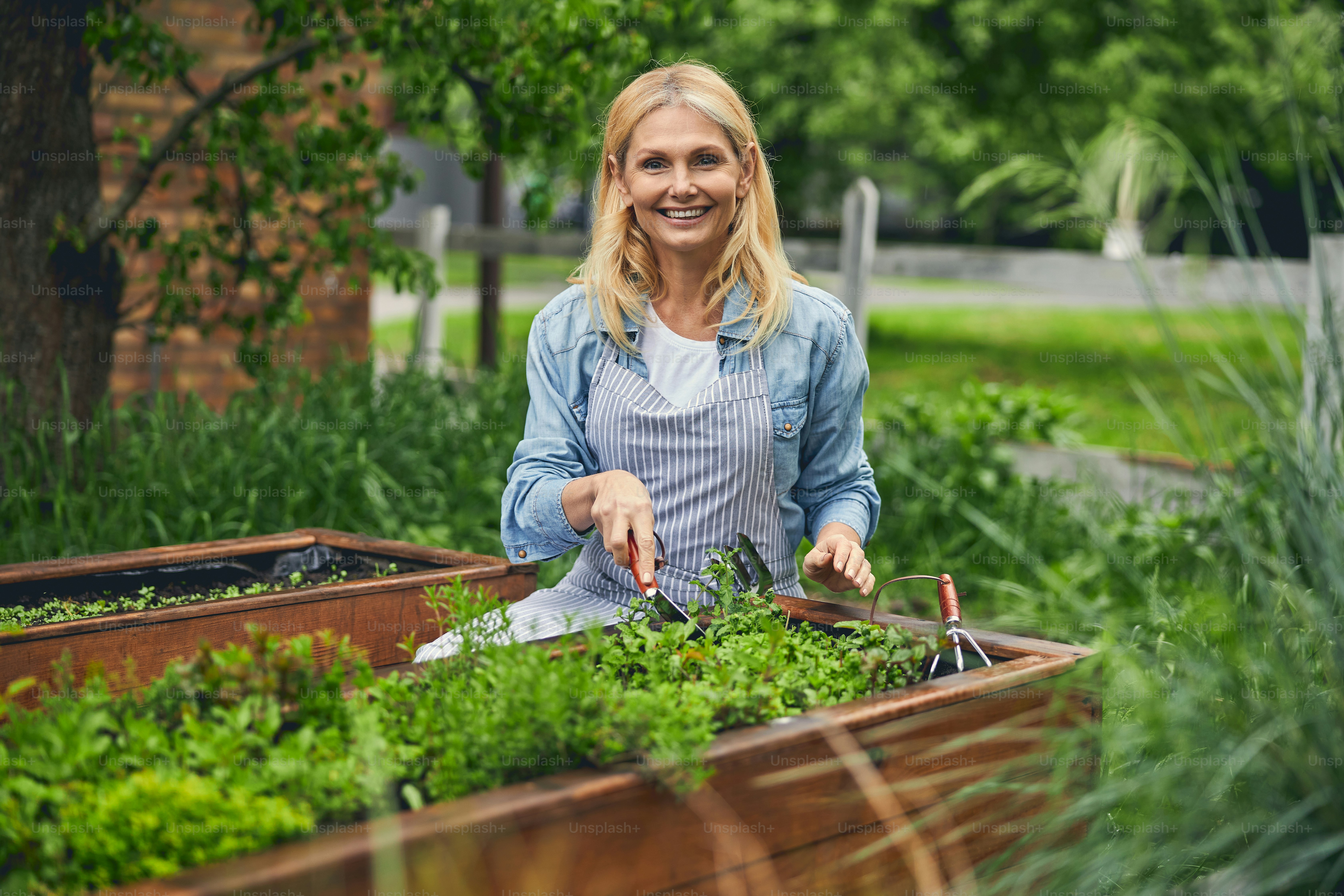 Front view of a pleased female horticulturist with a trowel in her hand ...