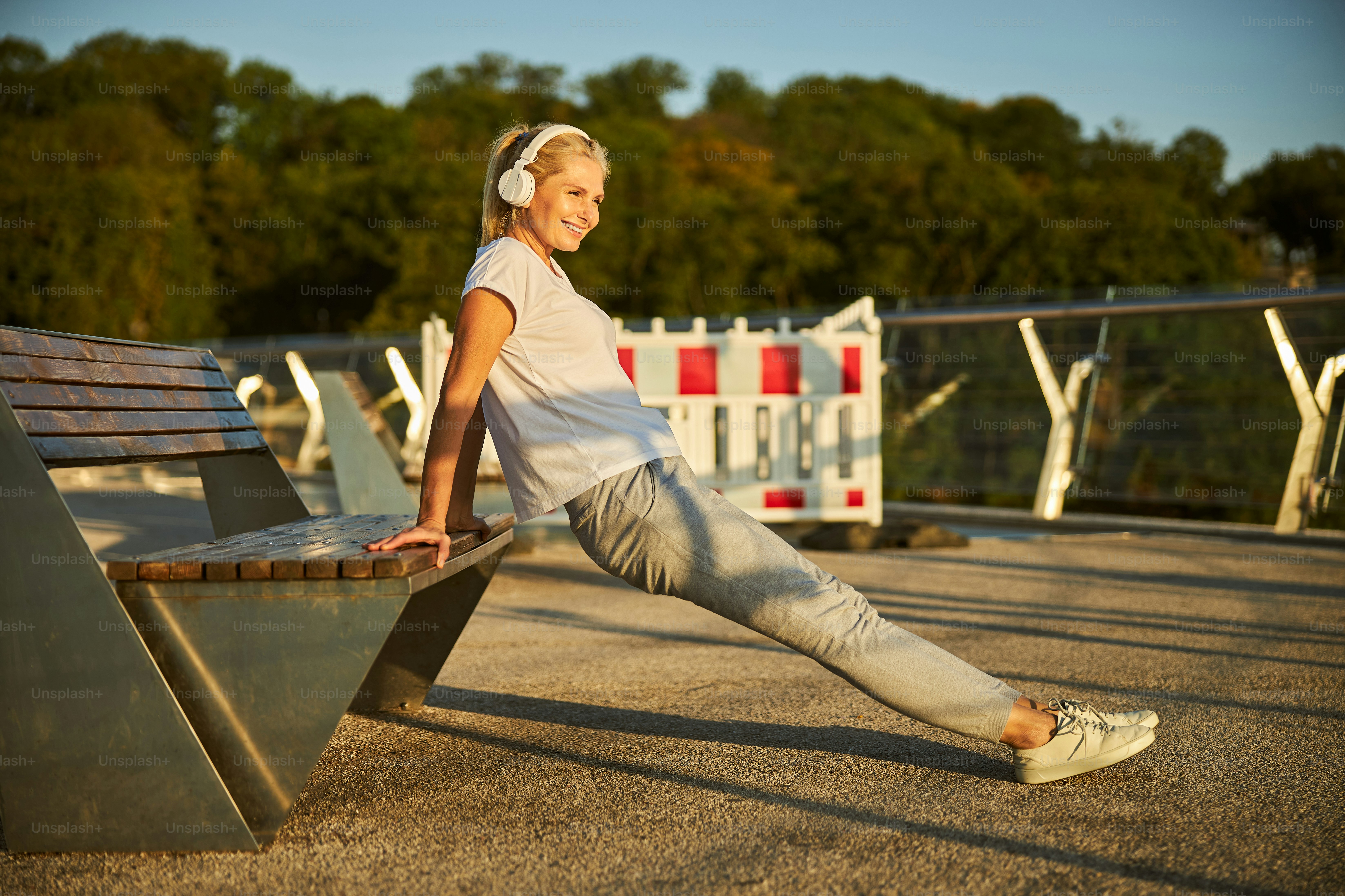 Charming lady in sportswear listening to music through wireless ...