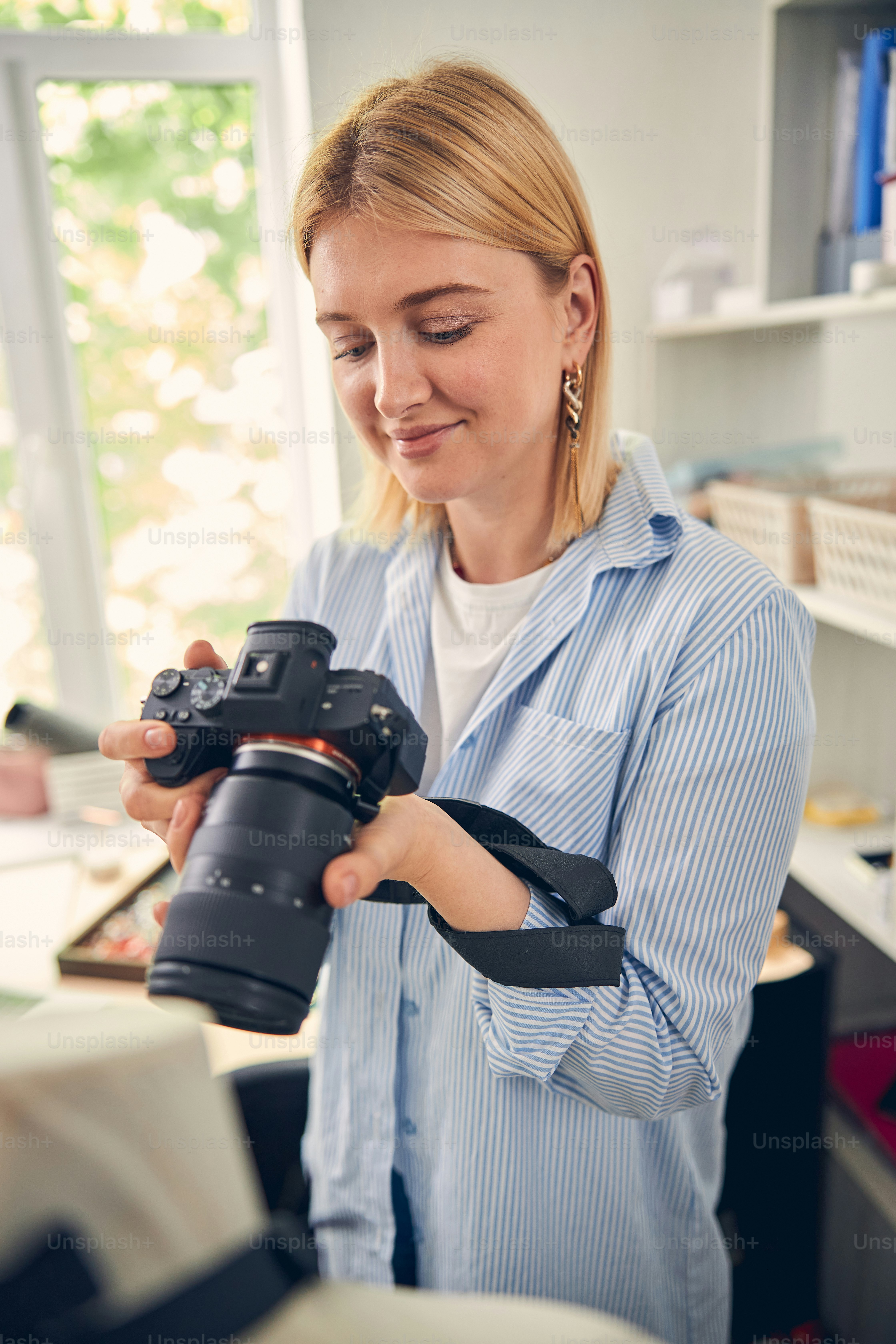 Optimistic photographer holding a camera and looking through recently ...