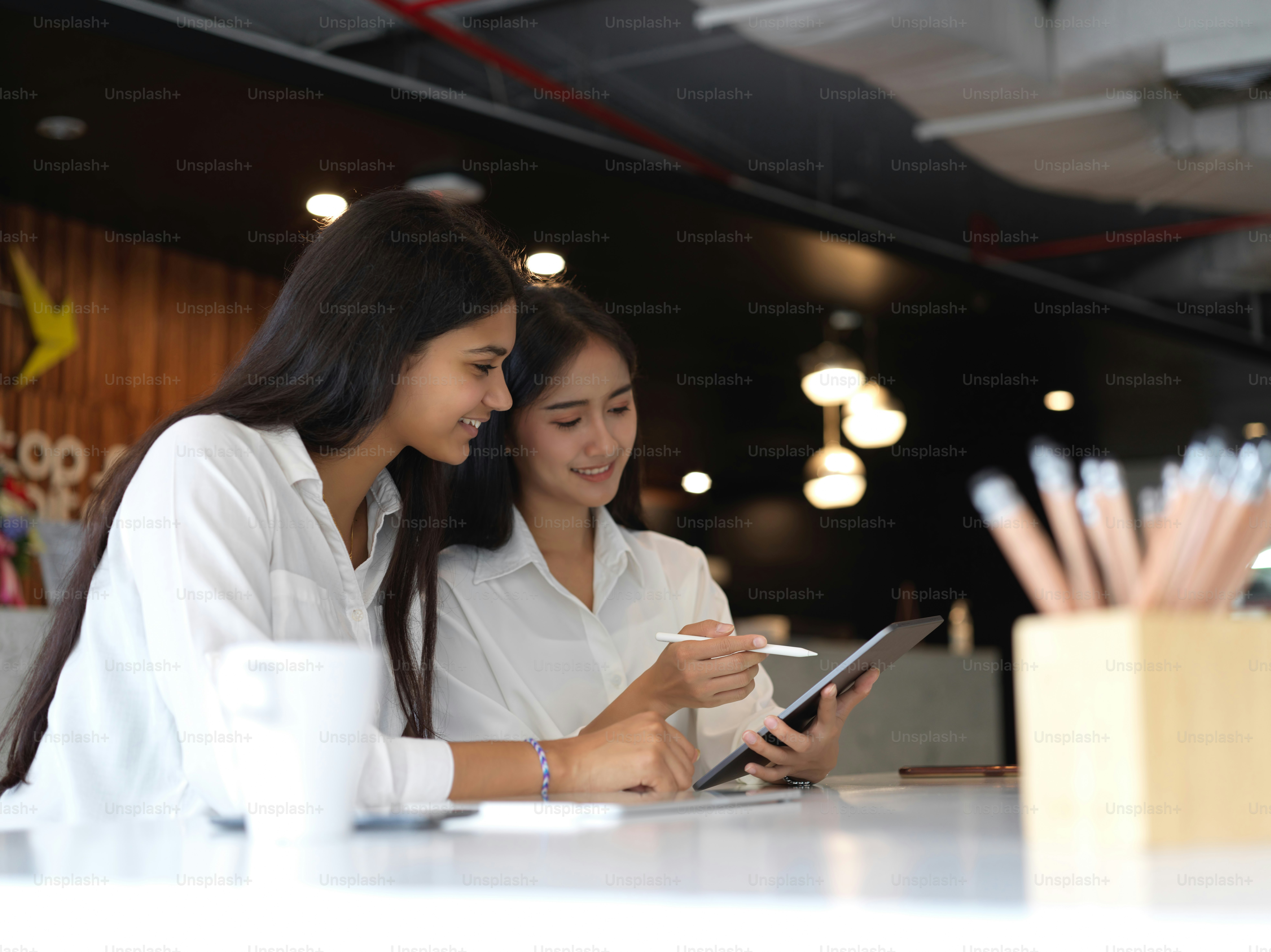 Side view of two female university students doing homework together ...