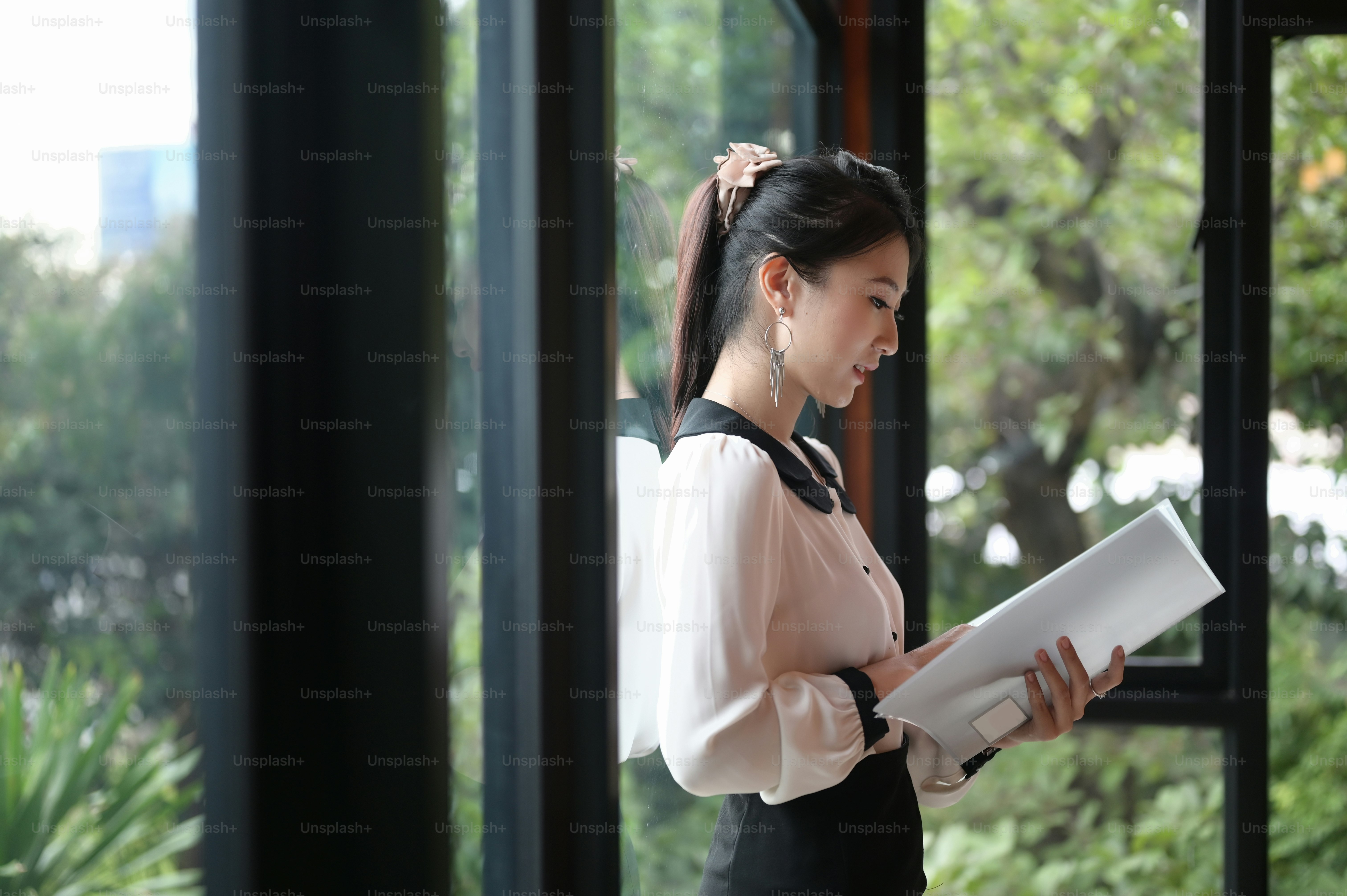 A businesswoman is checking paperwork while standing in the meeting ...