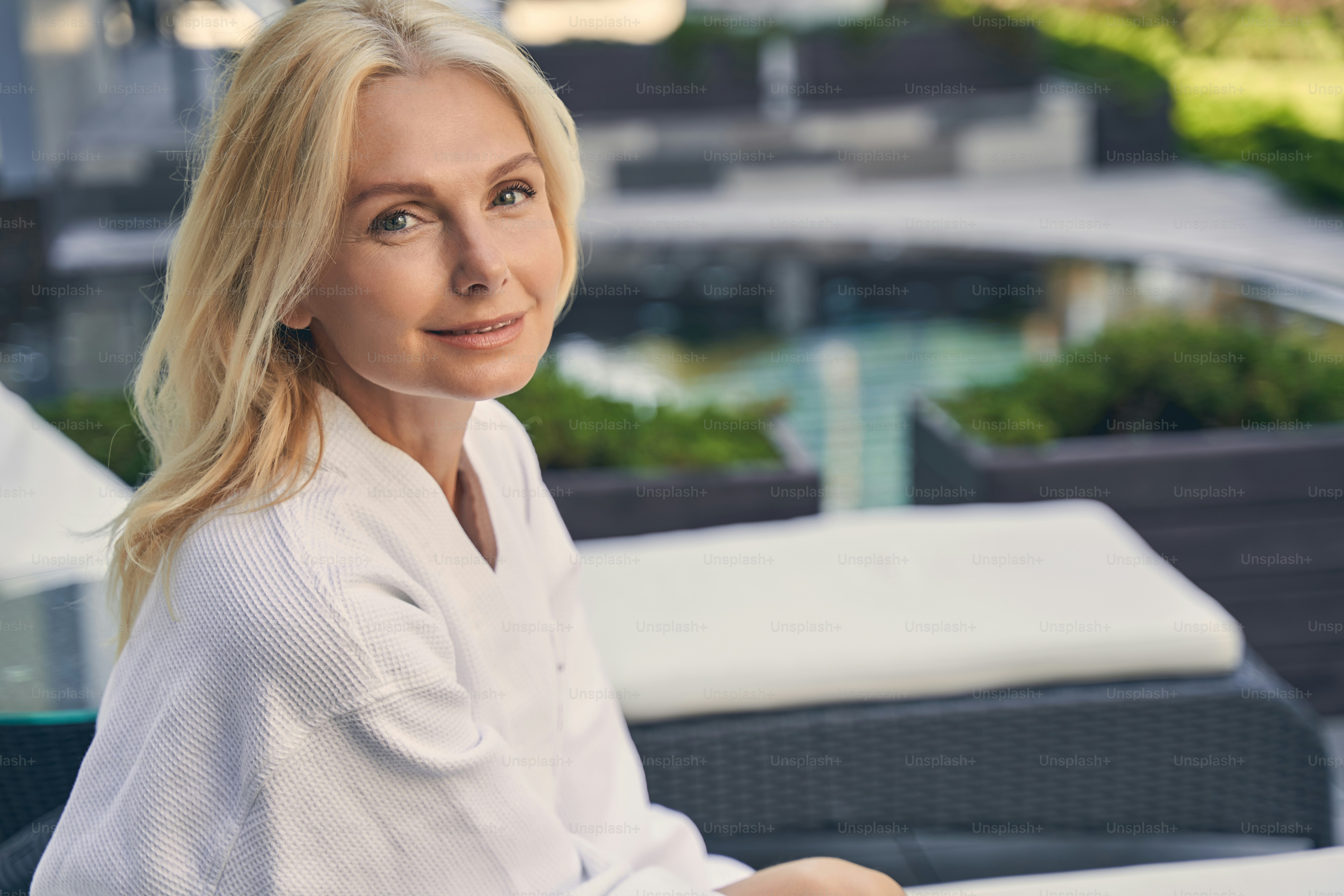 Portrait of charming lady in white soft bathrobe looking at the photo ...