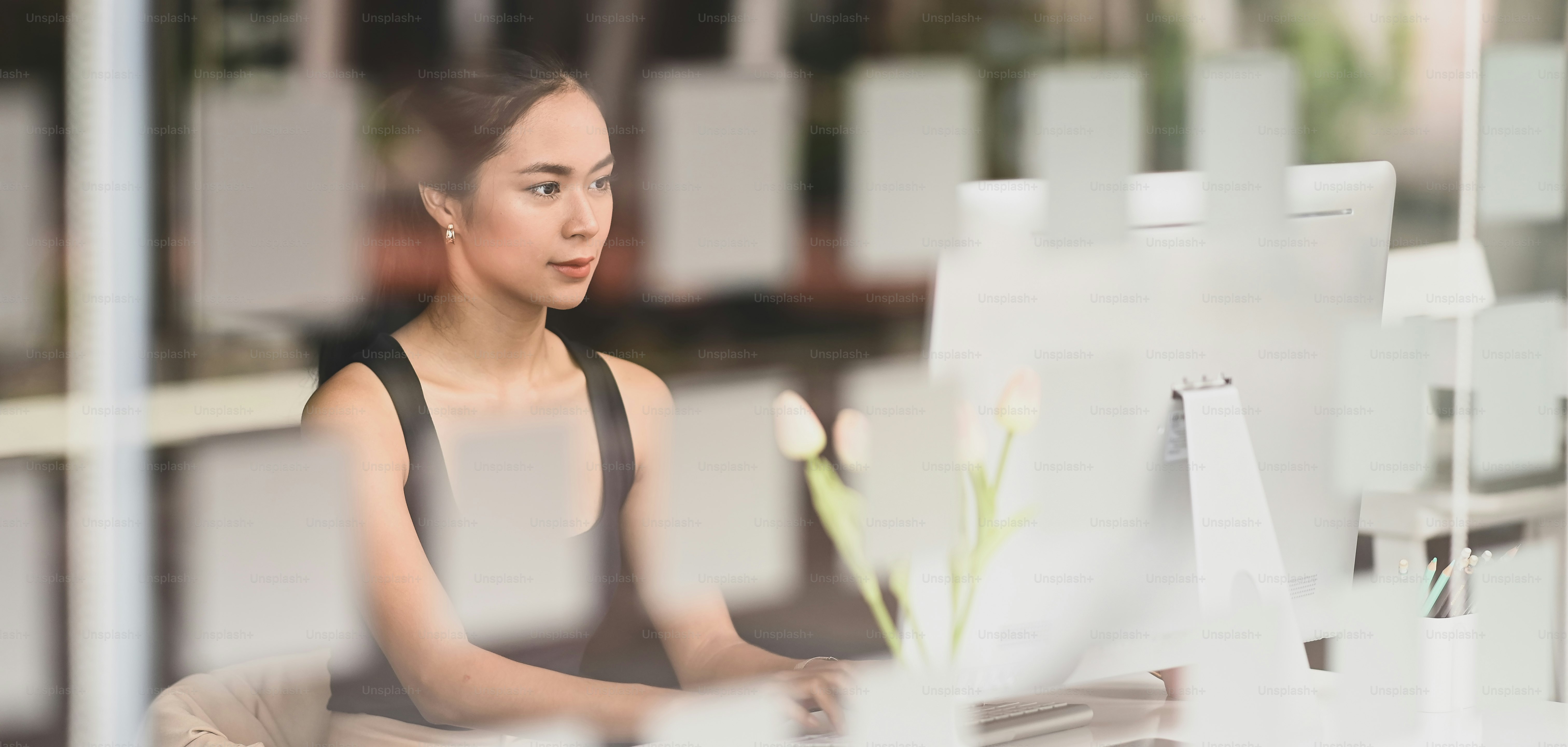 Foto zum Thema Eine Frau sitzt am Computer an einem modernen ...