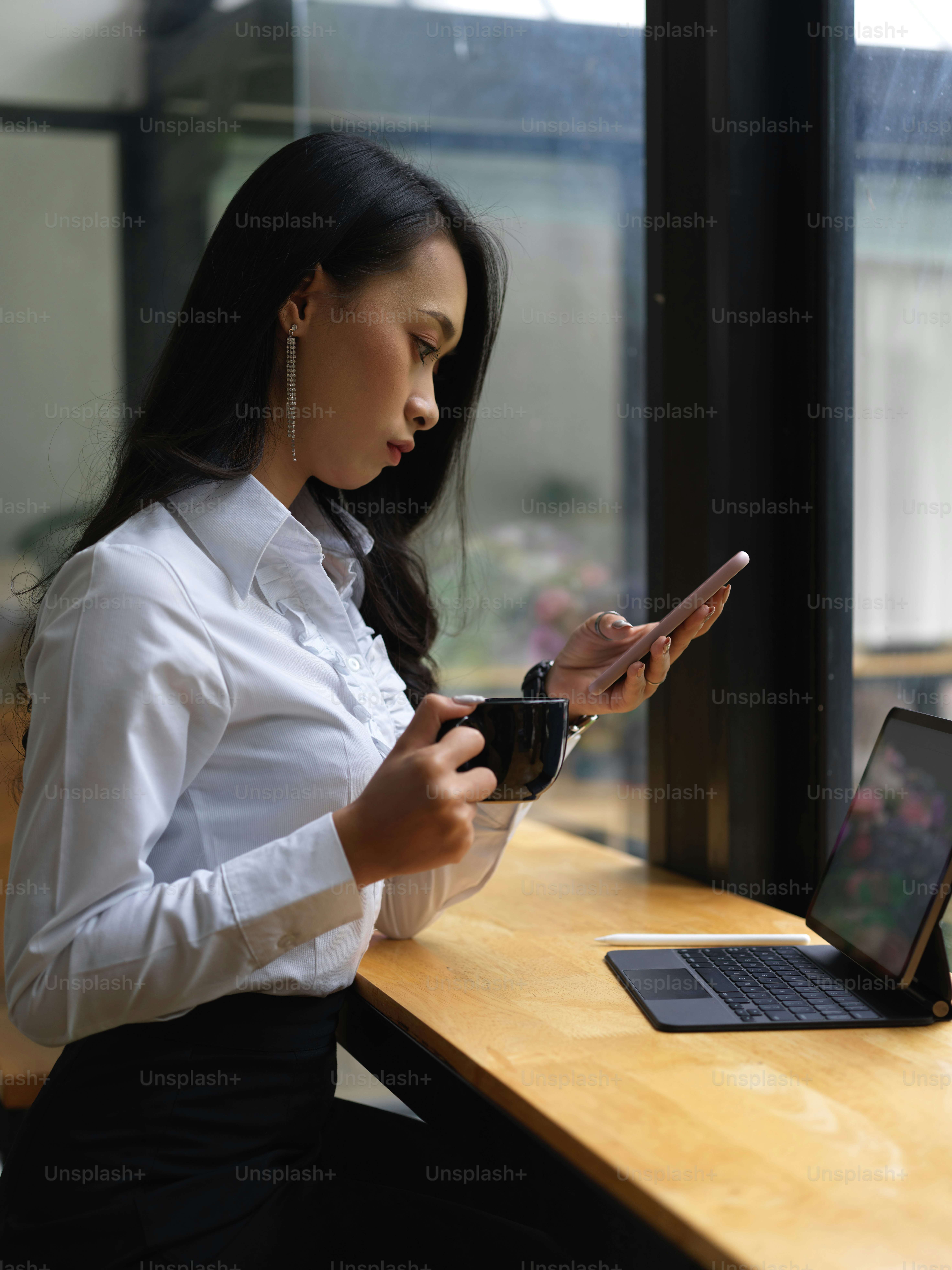 Side view of female texting on smartphone while holding coffee cup in ...