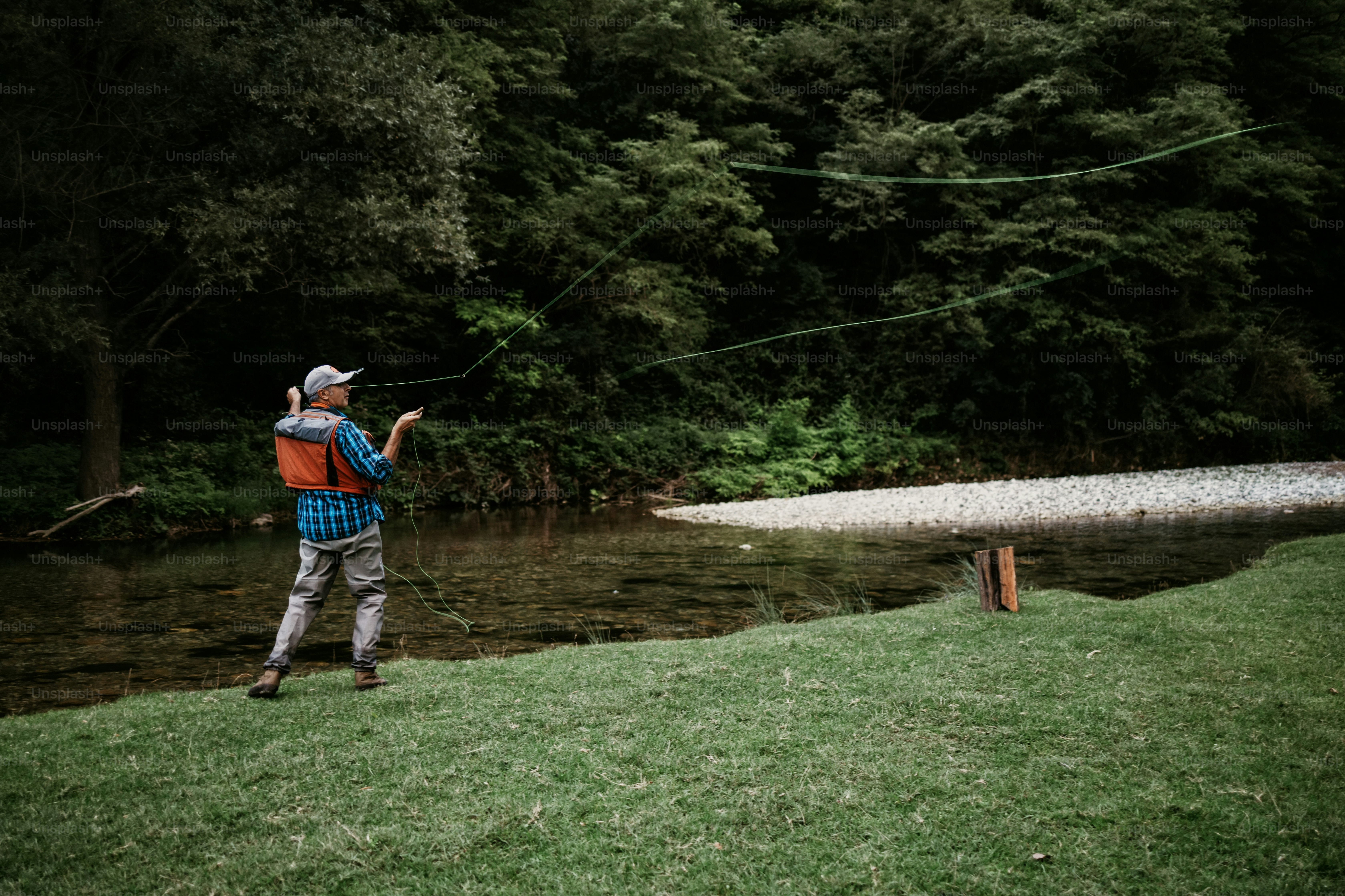 Senior man is fishing alone on fast mountain river. Active people and sport fly fishing concept ...