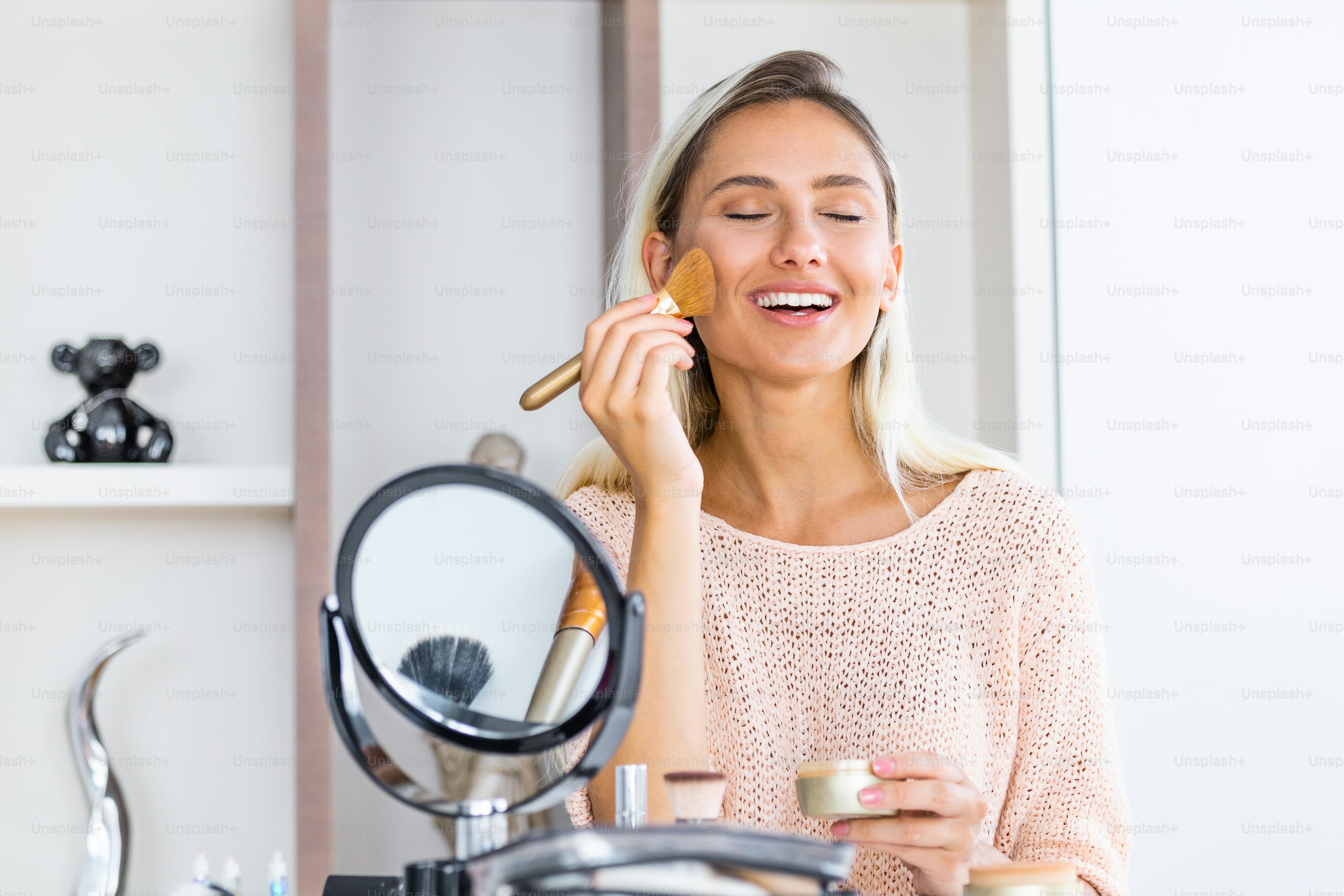 Beauty woman applying makeup. Beautiful girl looking in the mirror and ...
