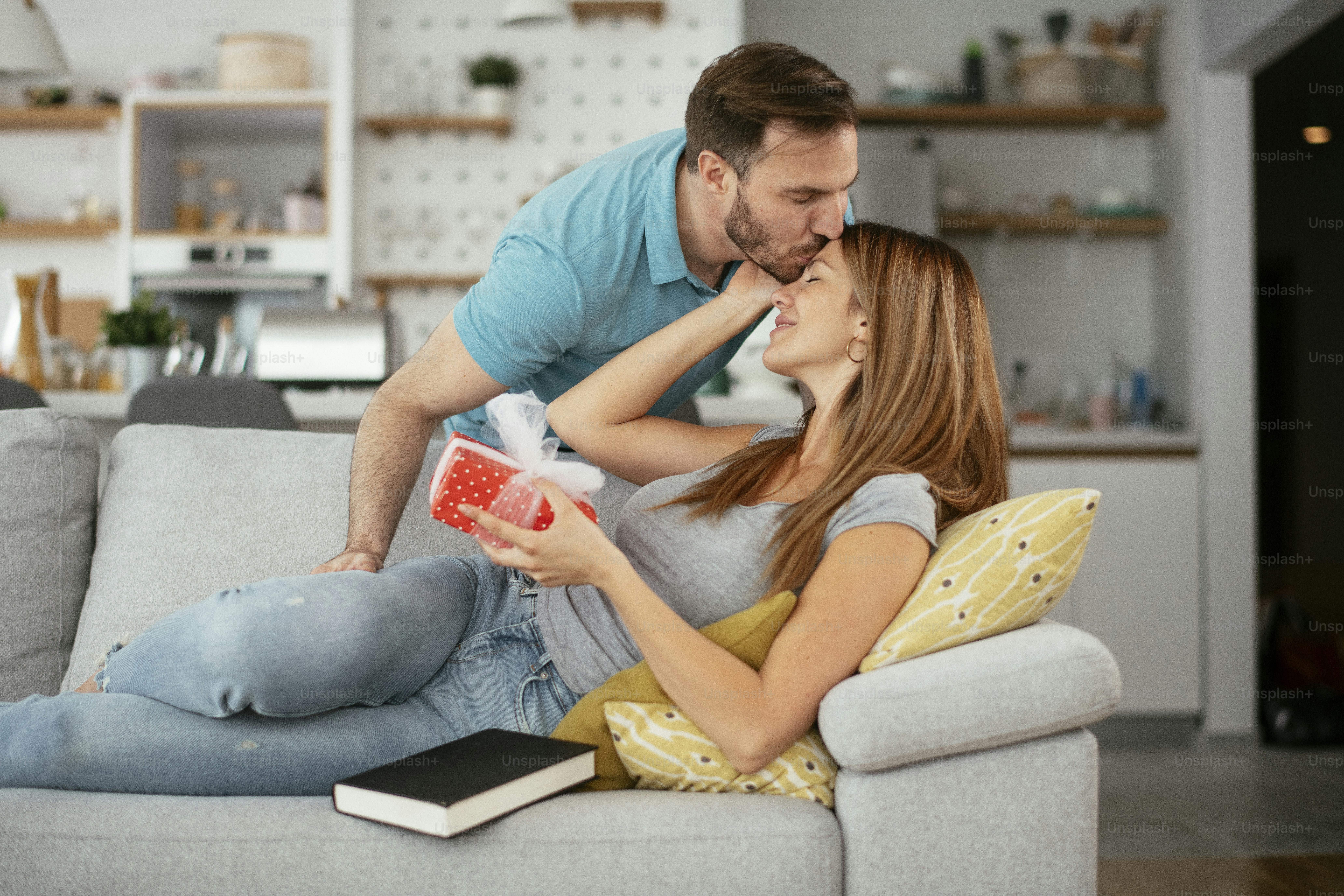 Husband surprising his wife with a gift. Young man giving gift box to ...