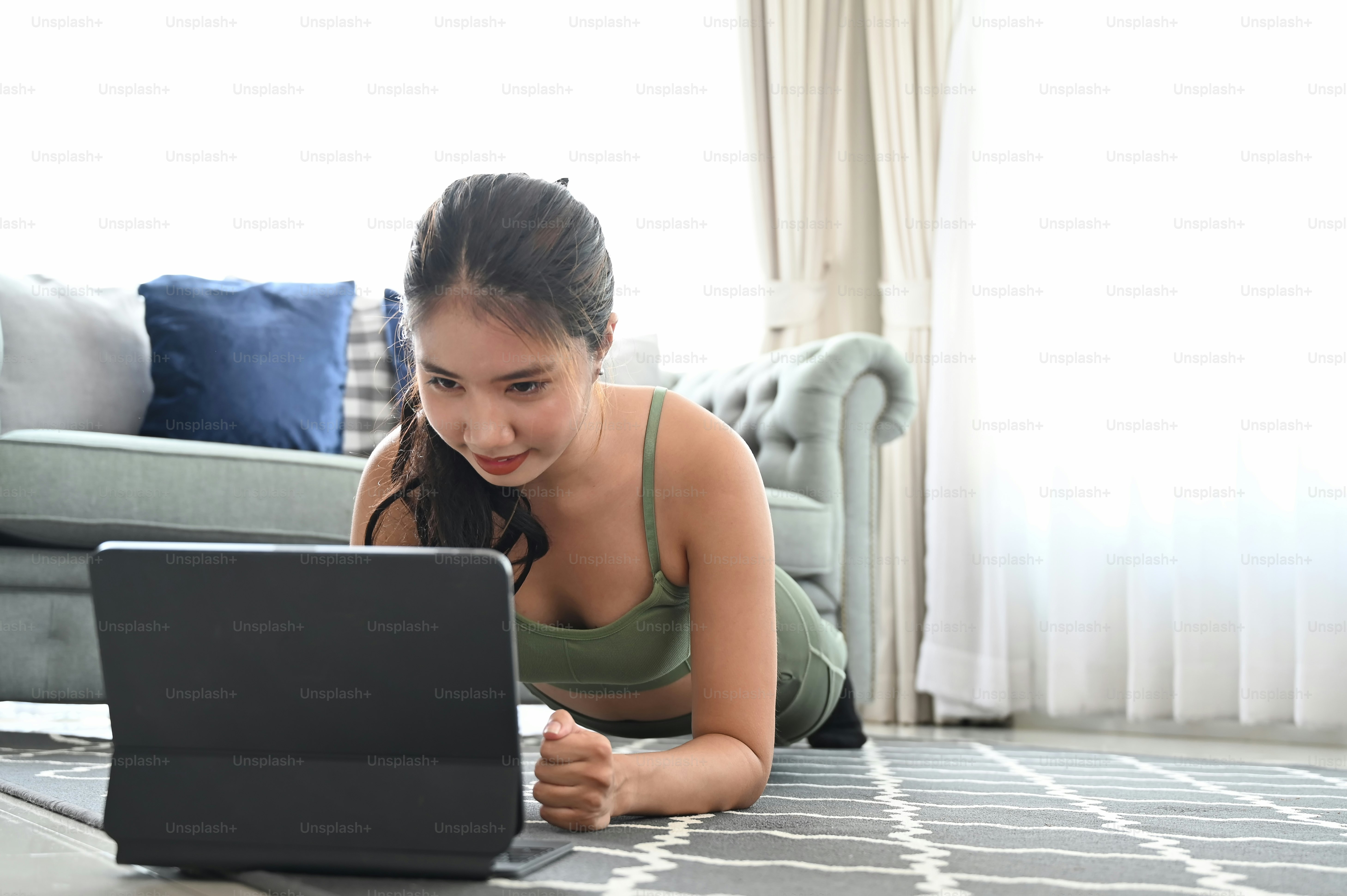 Foto Mujer atractiva que aprende nuevos ejercicios viendo tutoriales de entrenamiento en línea ...