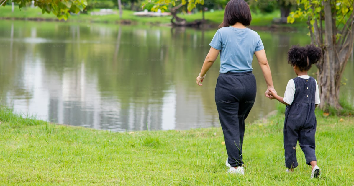 小さな娘が手をつないで公園を一緒に歩く幸せな混血の母親の後ろ姿。の写真 Unsplashの湖の画像