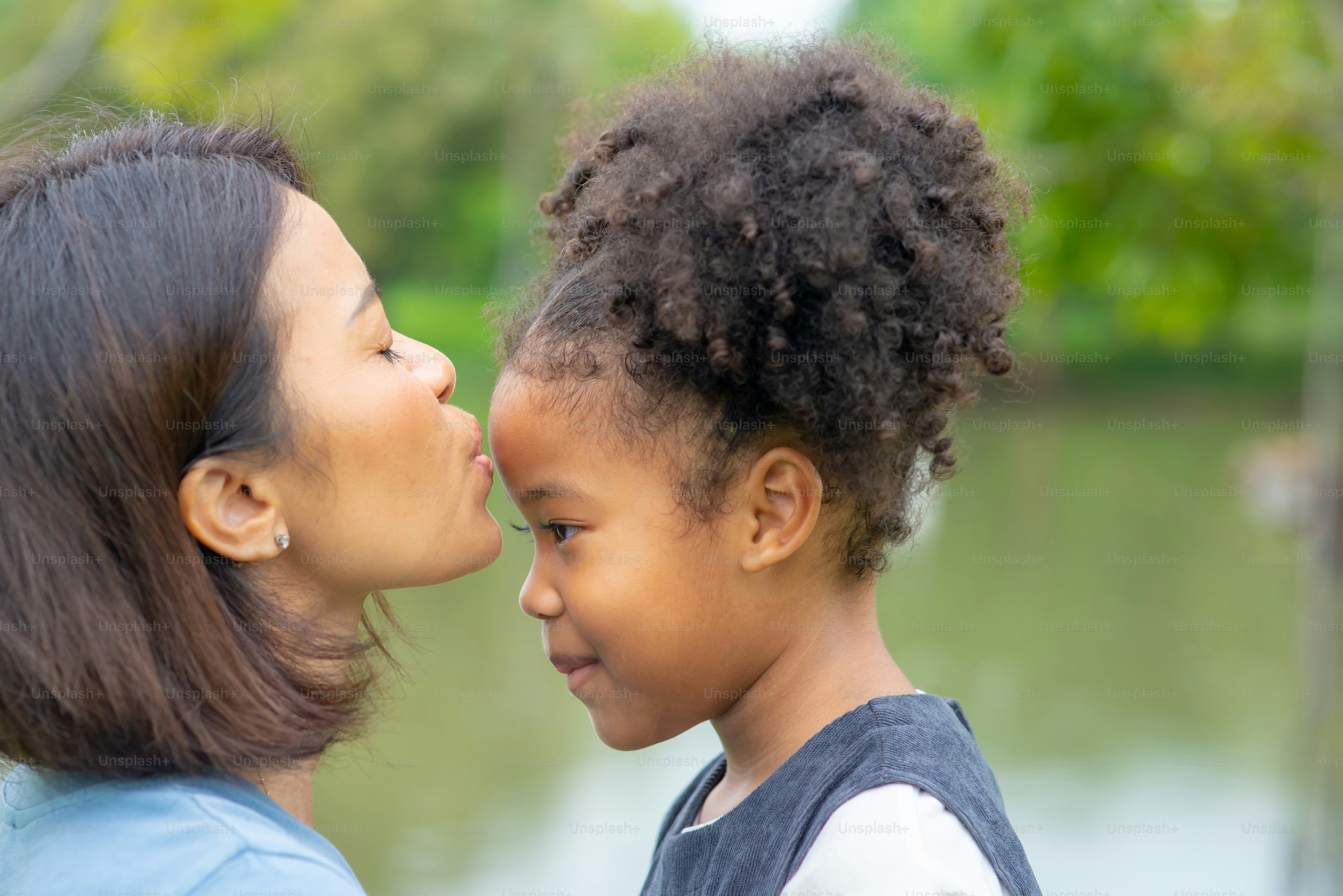 Mother kissing her mixed race daughter in the park photo – Thailand ...