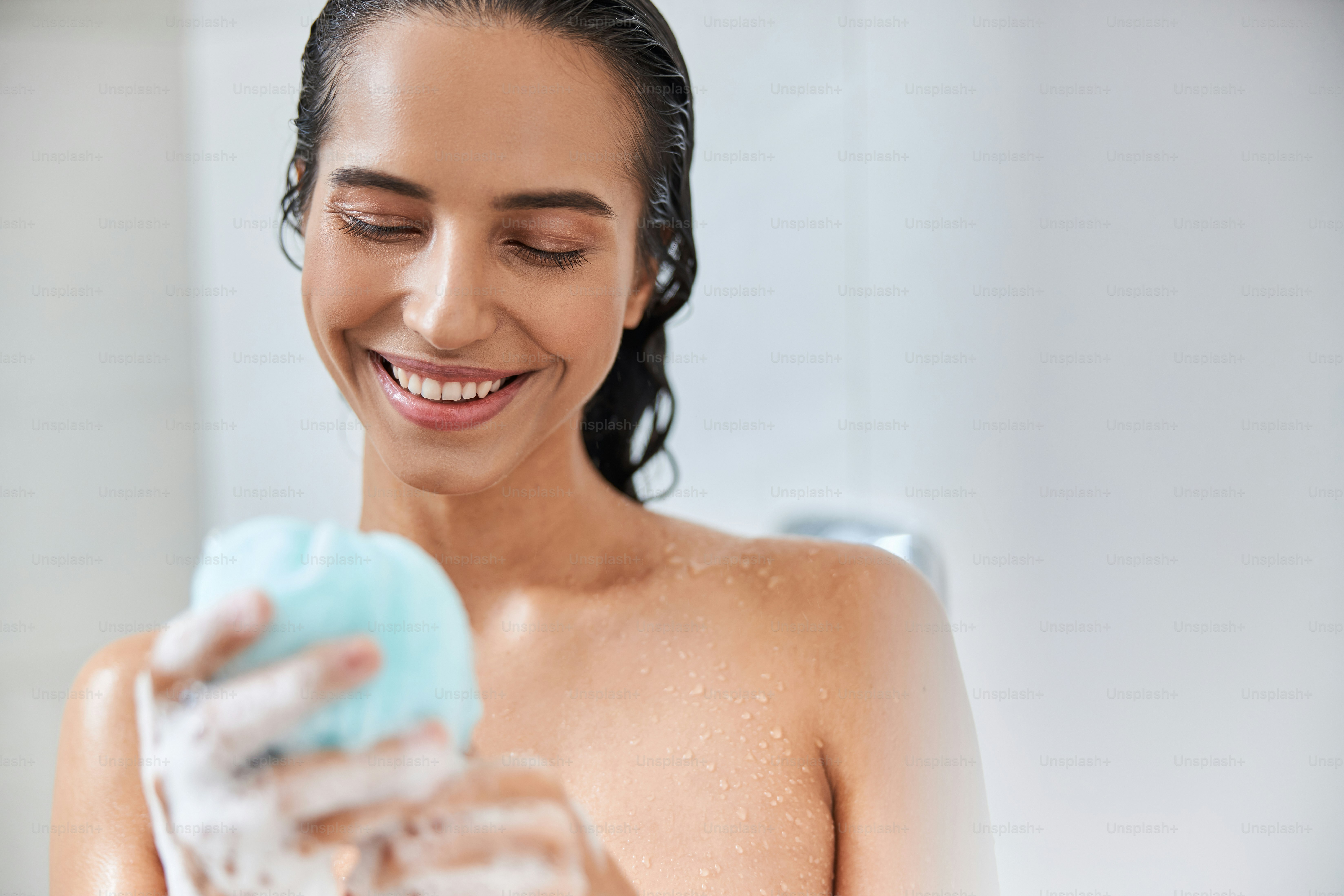 Beautiful smiling lady with exfoliating washcloth in her hand taking ...