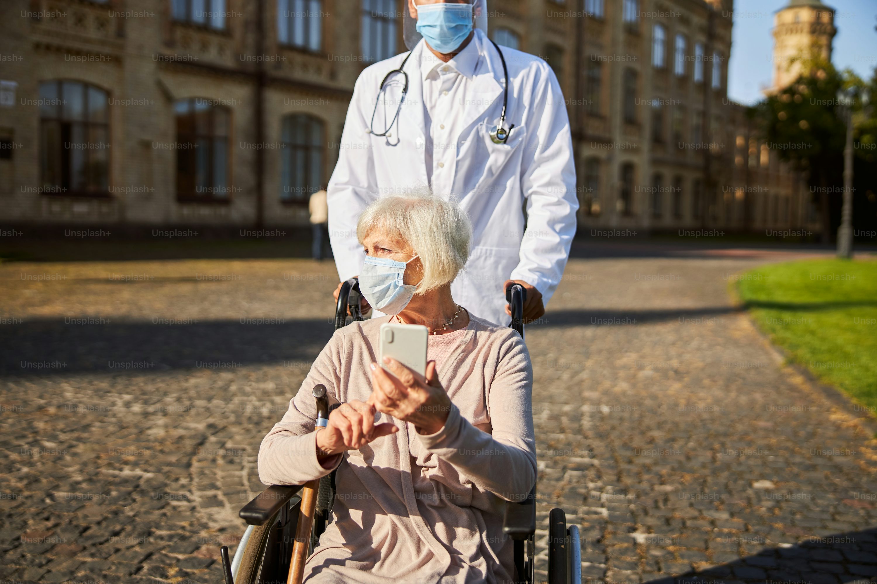 Aged woman with disability holding a smartphone and looking away while ... Aged woman with disability holding a smartphone and looking away while ...